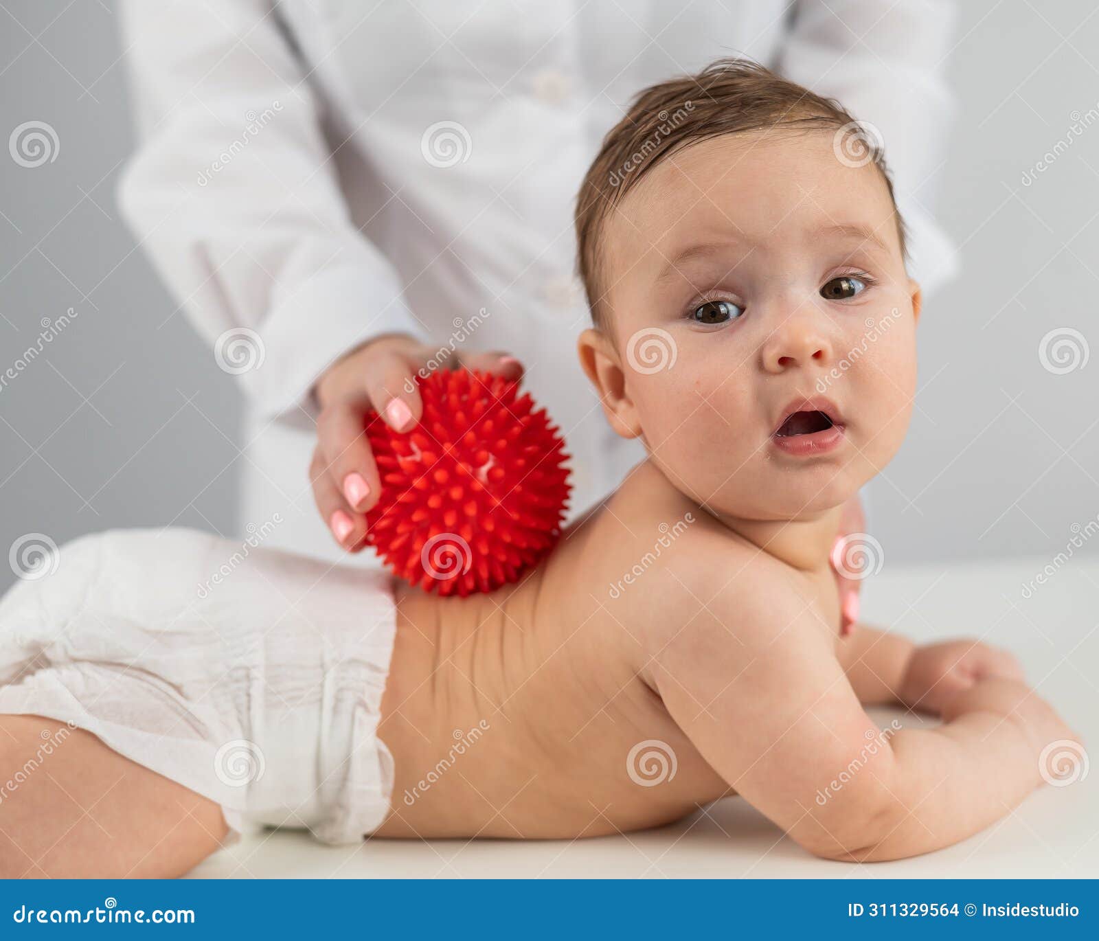 A Doctor Gives a Child a Back Massage Using a Ball. Stock Photo - Image ...