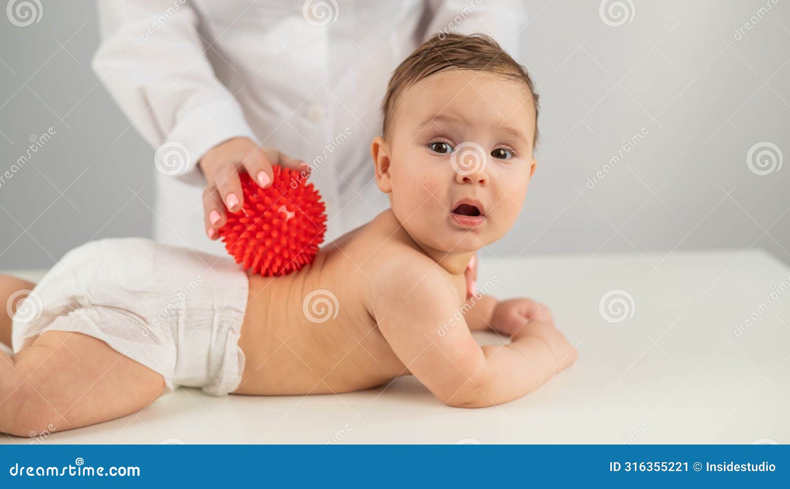 A Doctor Gives a Child a Back Massage Using a Ball. Stock Image - Image ...