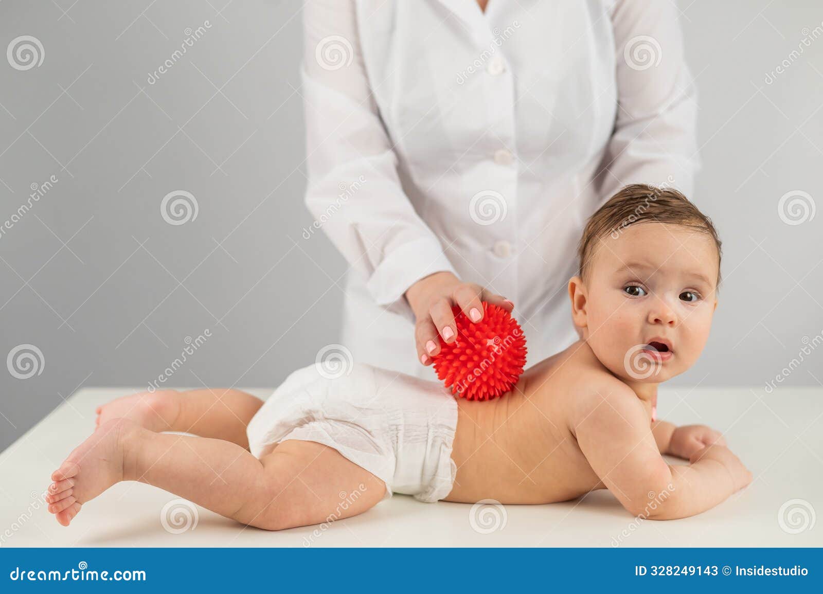 A Doctor Gives a Child a Back Massage Using a Ball. Stock Image - Image ...