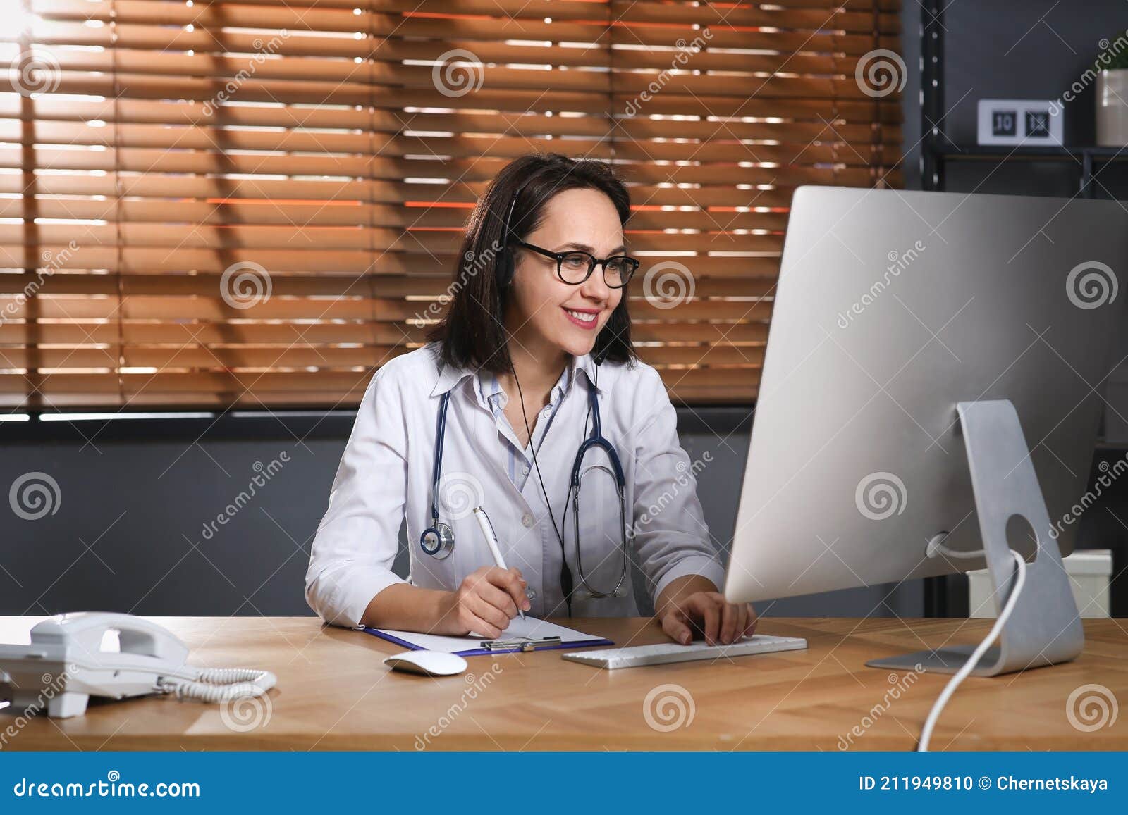 Doctor with Headset and Computer Consulting Patient Online in Office ...