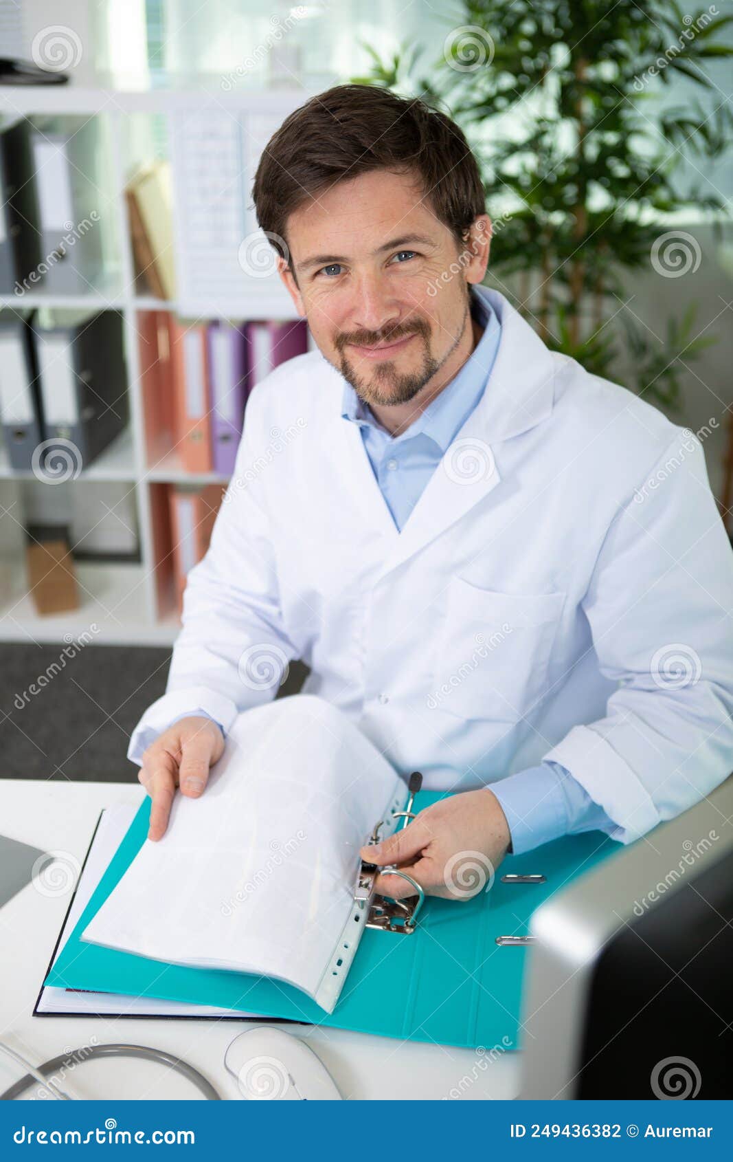 Doctor Looking at File while Sitting at Desk in Hospital Stock Photo ...