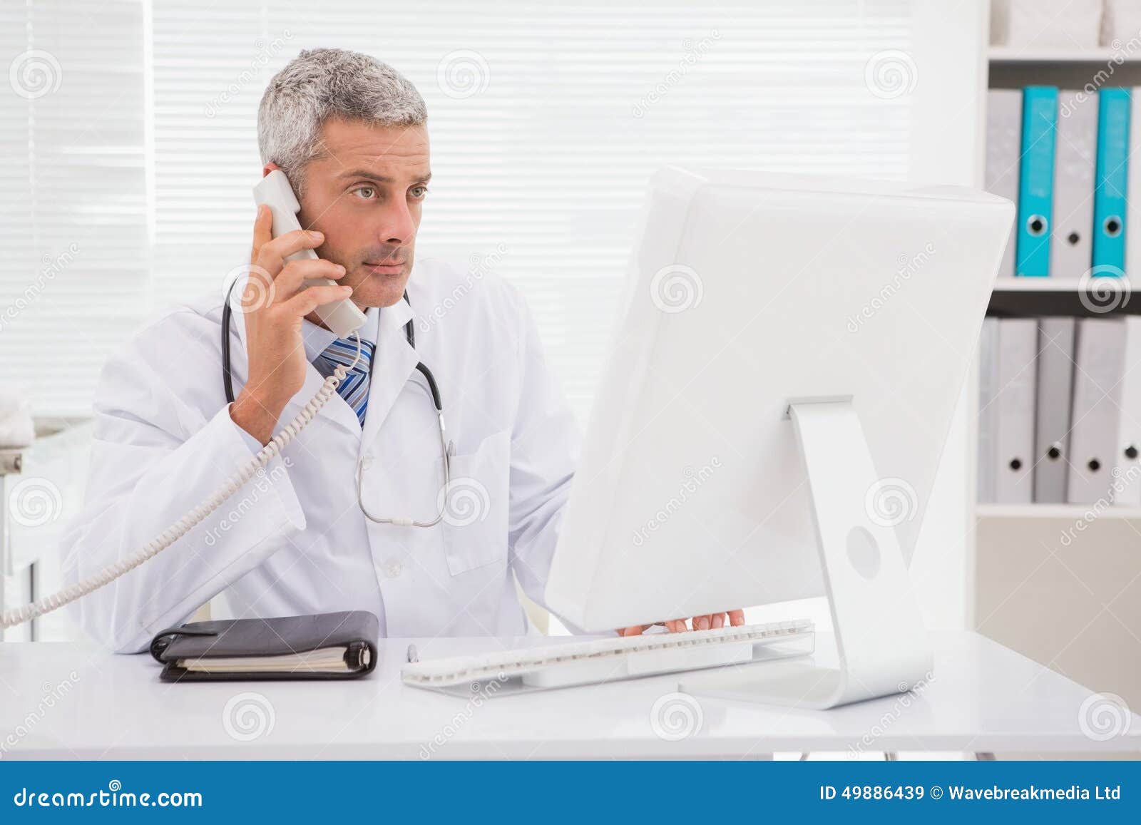 Doctor Phoning and Using Computer Stock Image - Image of office ...