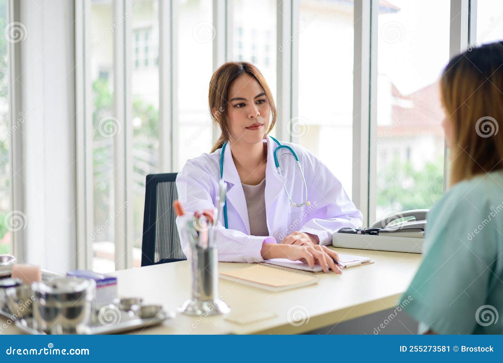 Doctor Questioning Patient in Office and Writing Answers in Clipboard ...