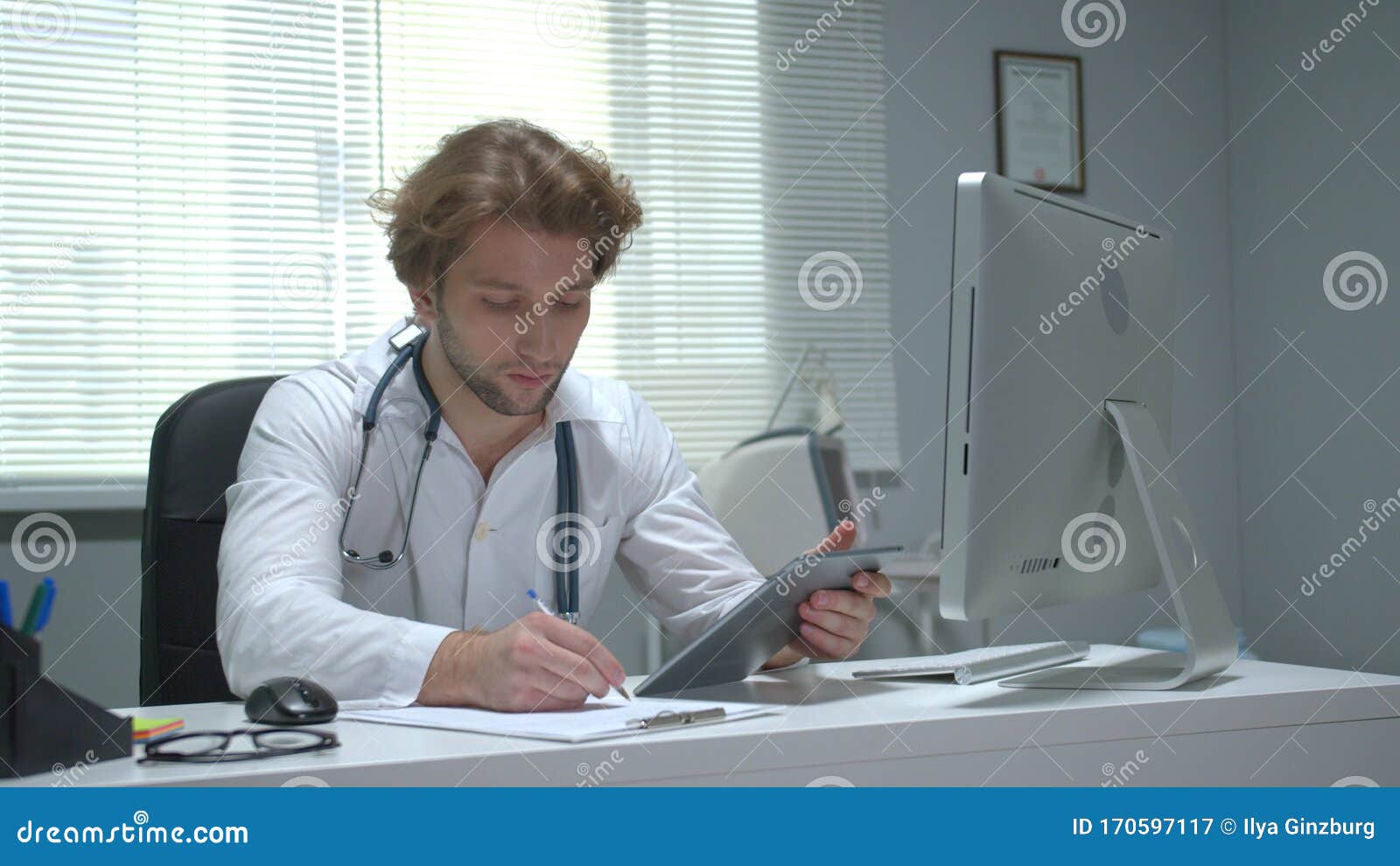 Doctor Sit at a Table in Cabinet of Hospital and Work with Tablet Stock ...