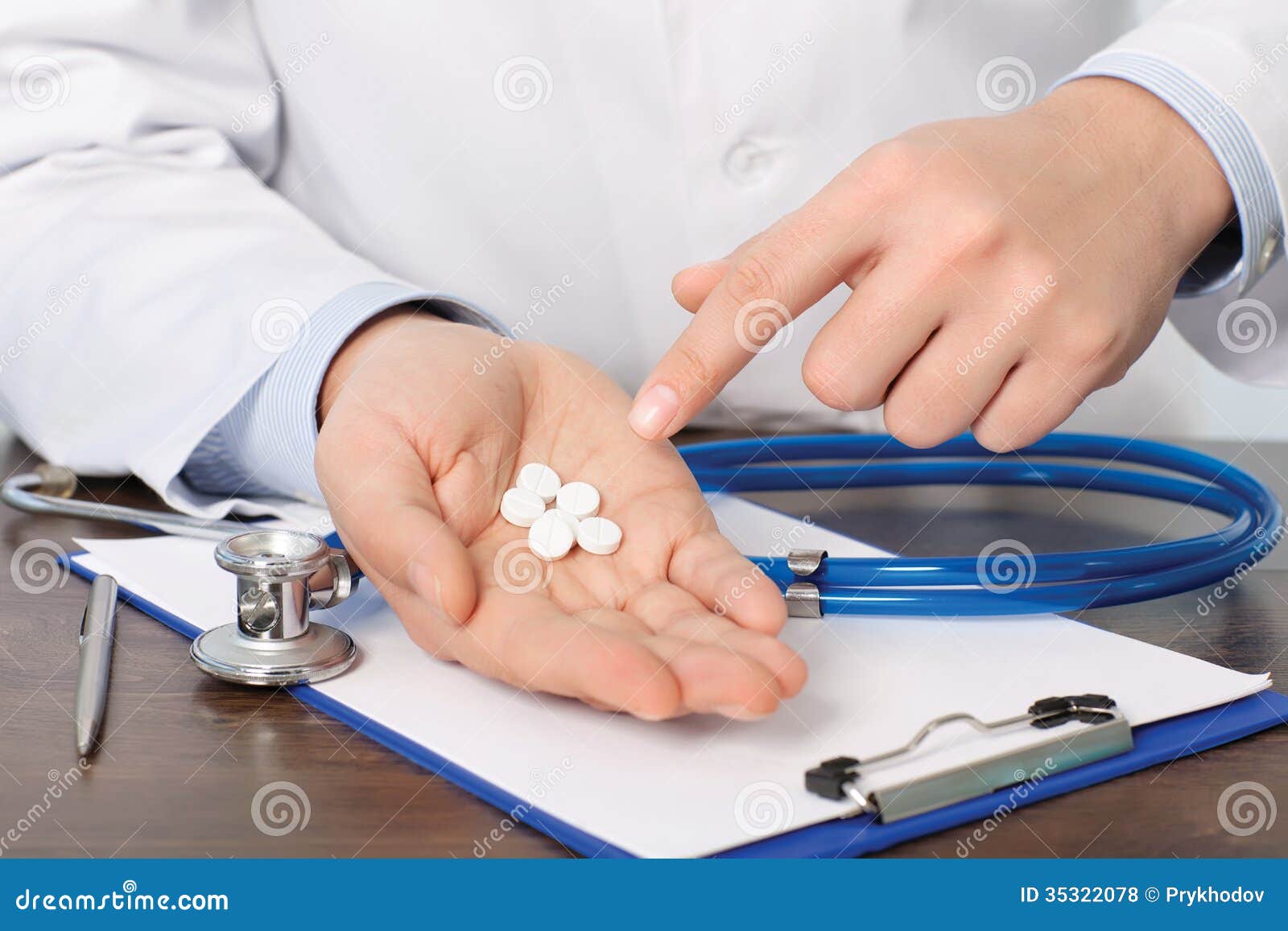 Doctor Sitting at a Table with Stethoscope and Holding a Pills Stock ...