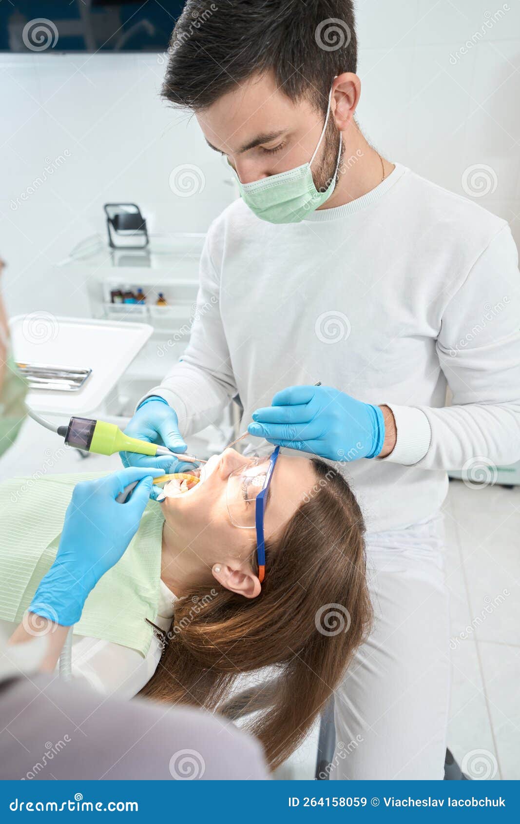 Doctor Treating Caries In Young Woman Assisted By Nurse Stock Image