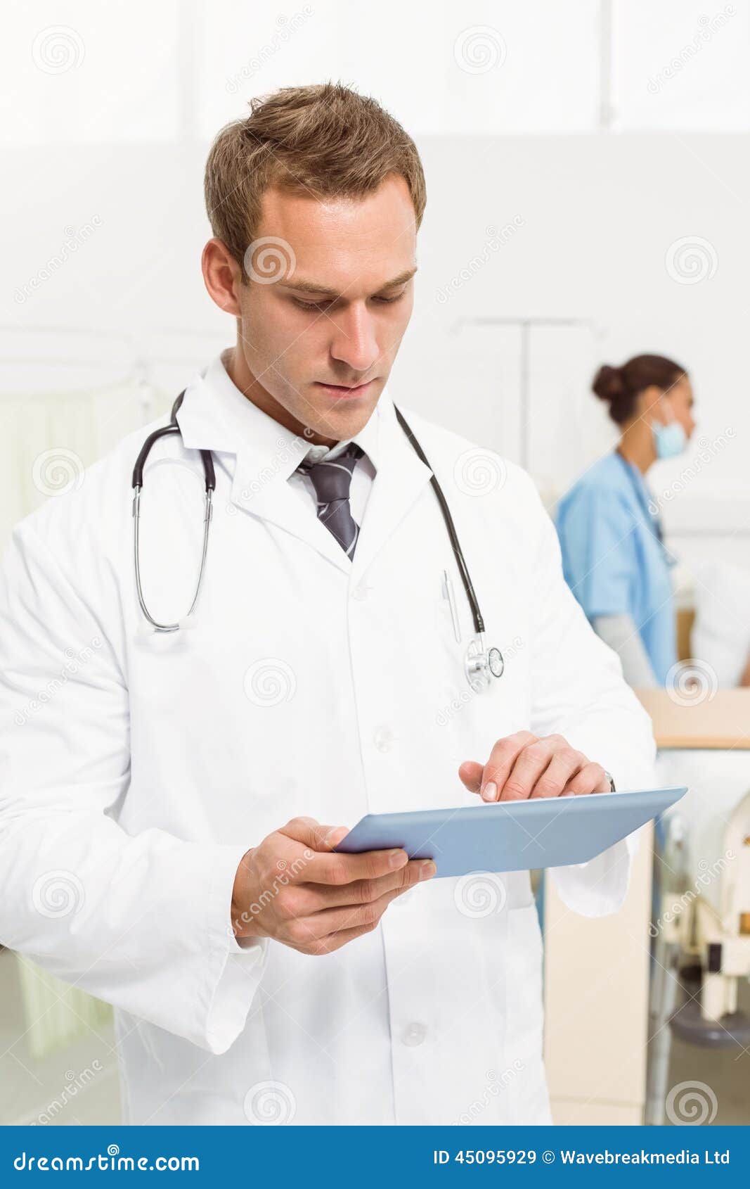Doctor Using Digital Tablet with Colleagues and Patient Behind Stock ...