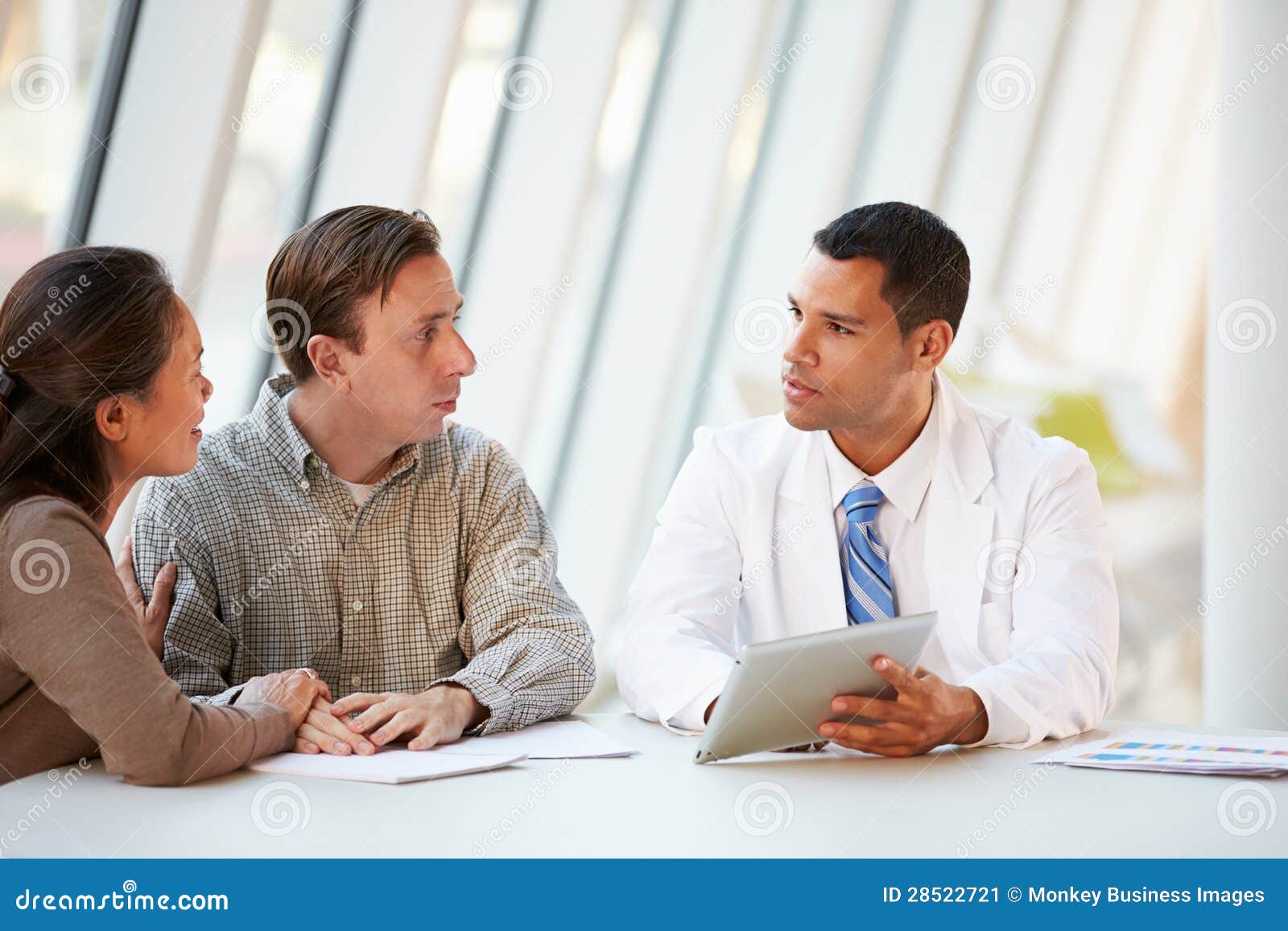 Doctor Using Tablet Computer Discussing Treatment with Patients Stock ...
