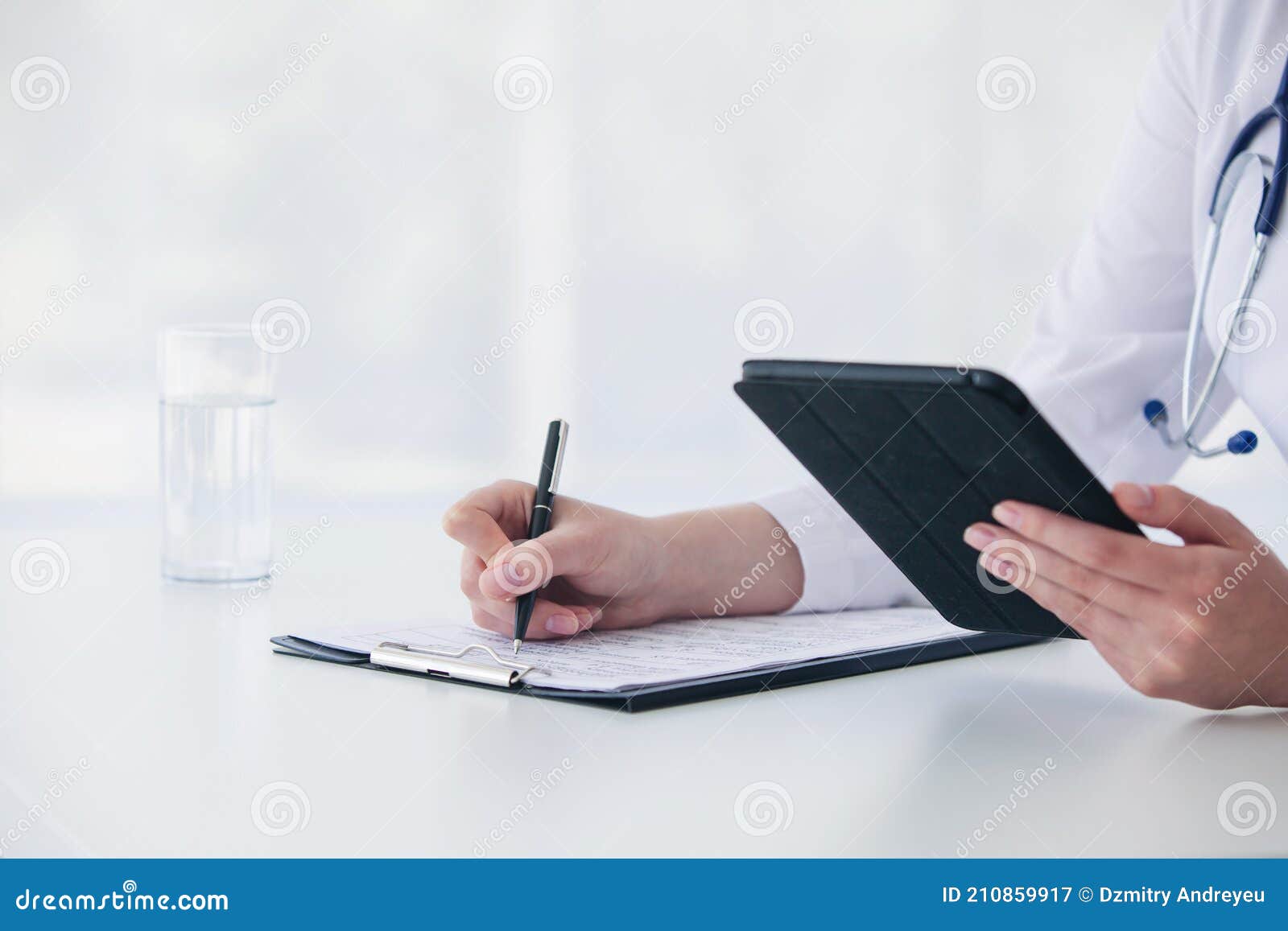 Doctor Using Tablet and Writing Diagnosis in Medical Forms Documents ...
