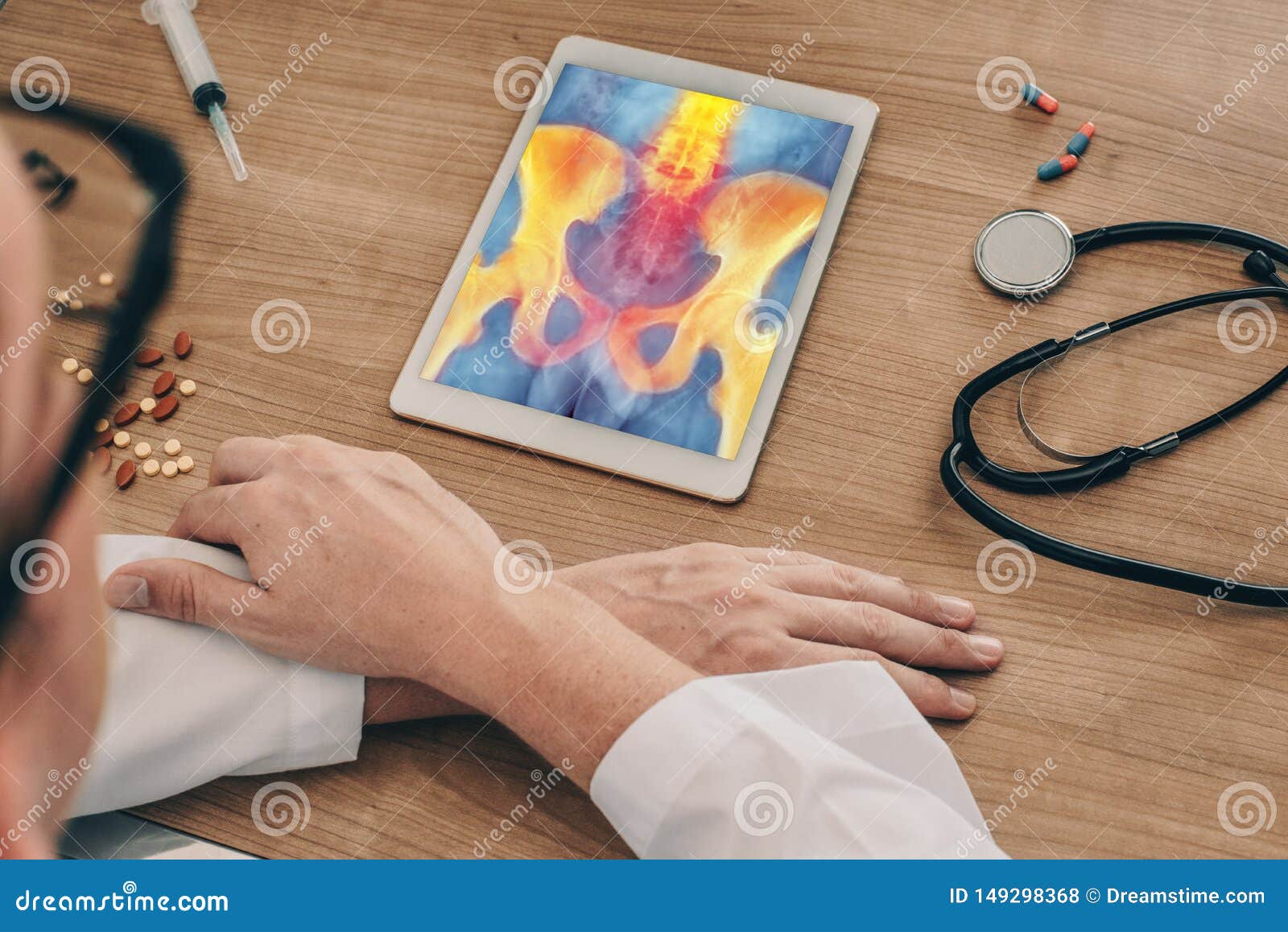 Doctor Watching a Digital Tablet with X-ray of Pain in the Hips and the ...