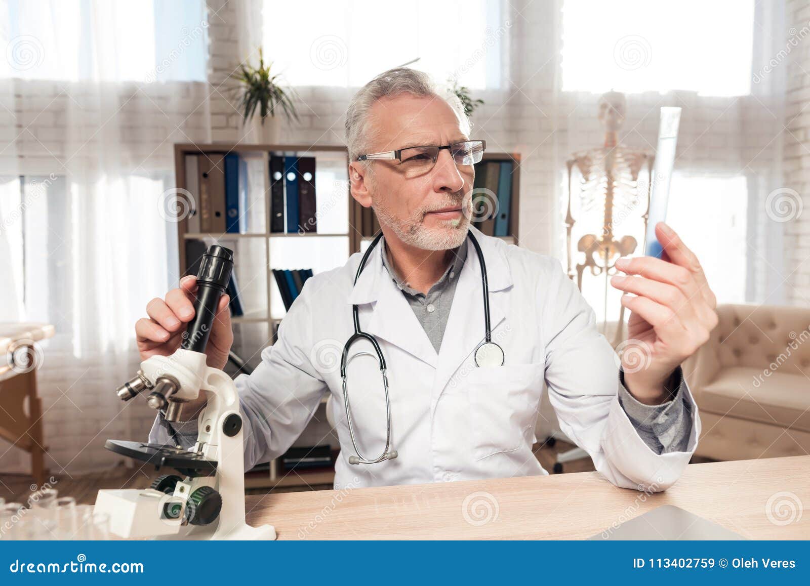 Doctor Sitting at Desk in Office with Microscope and Stethoscope. Man ...
