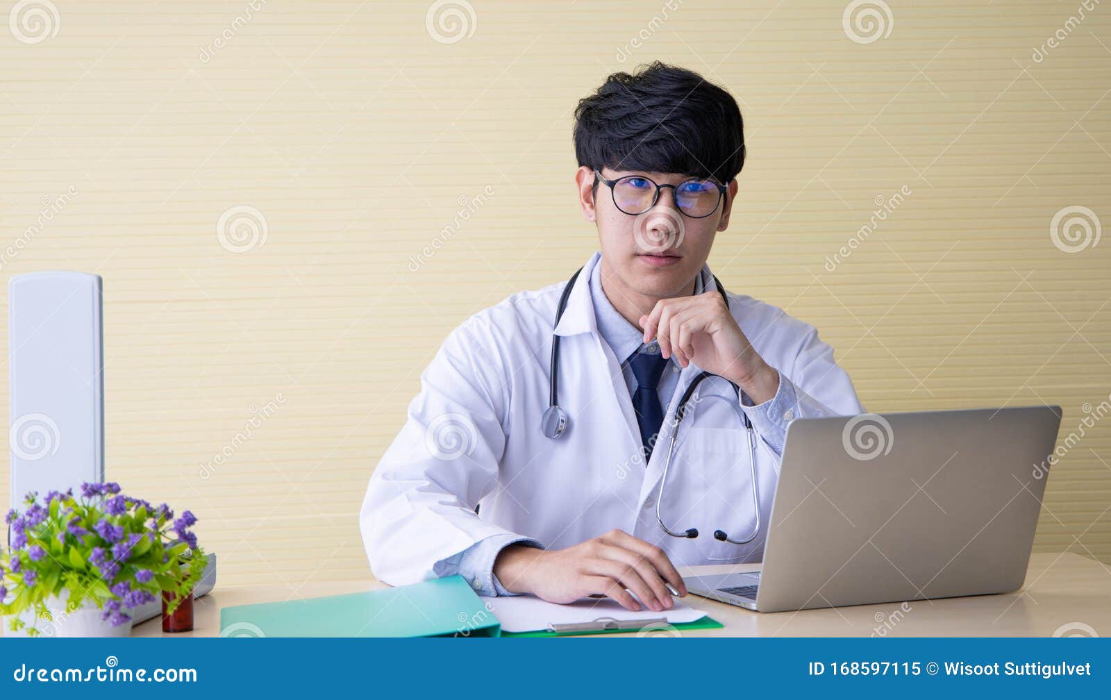 Doctor Working with Laptop Computer and Writing on Paperwork Stock ...