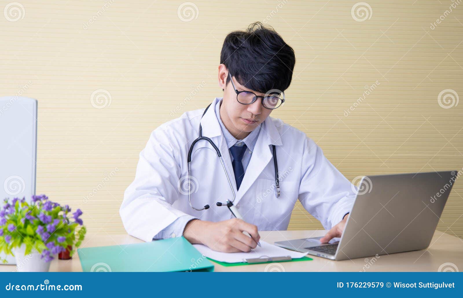 Doctor Working with Laptop Computer and Writing on Paperwork Stock ...