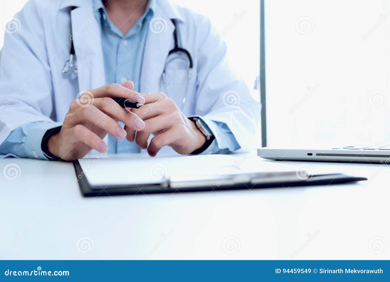 Doctor Working with Laptop Computer and Writing on Paperwork Stock ...