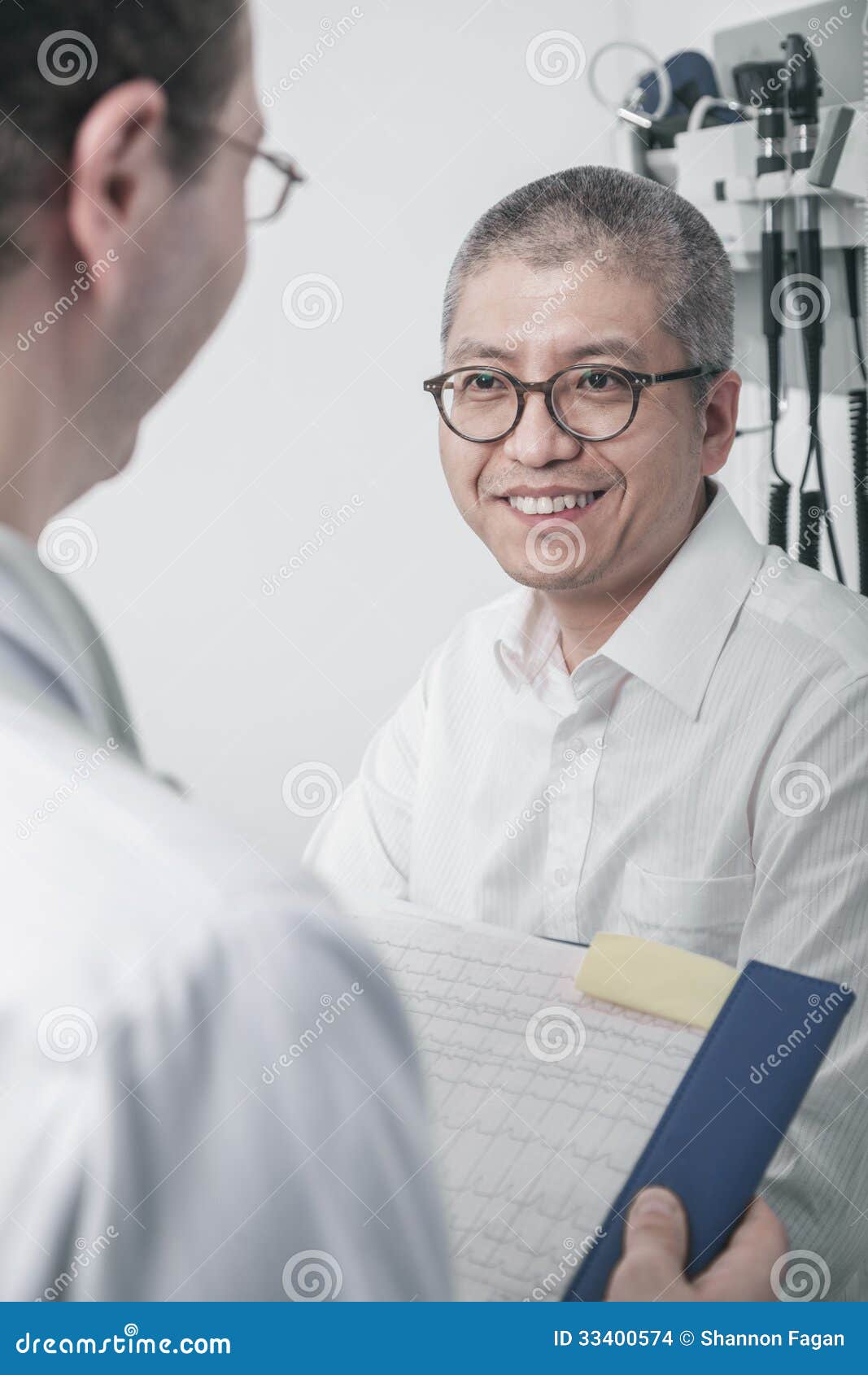 Doctor Writing on Medical Chart with a Smiling Patient Stock Photo ...