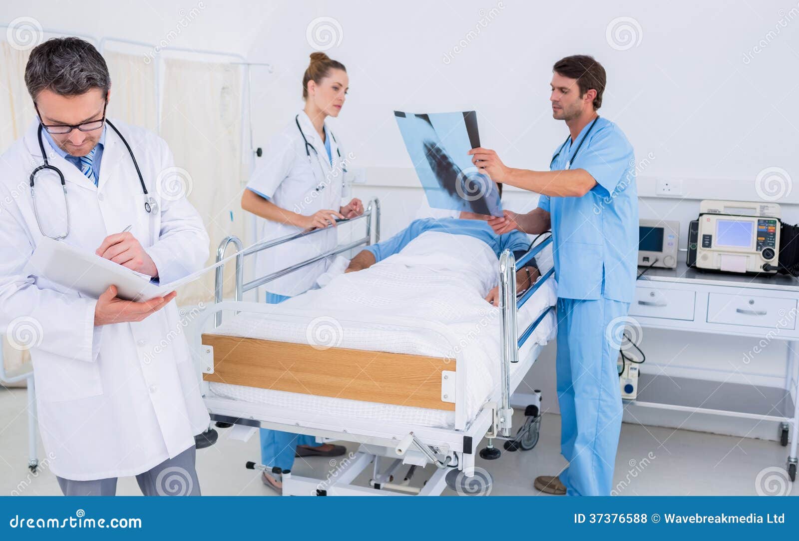 Doctors Holding Reports by Patient in at Hospital Stock Photo - Image ...