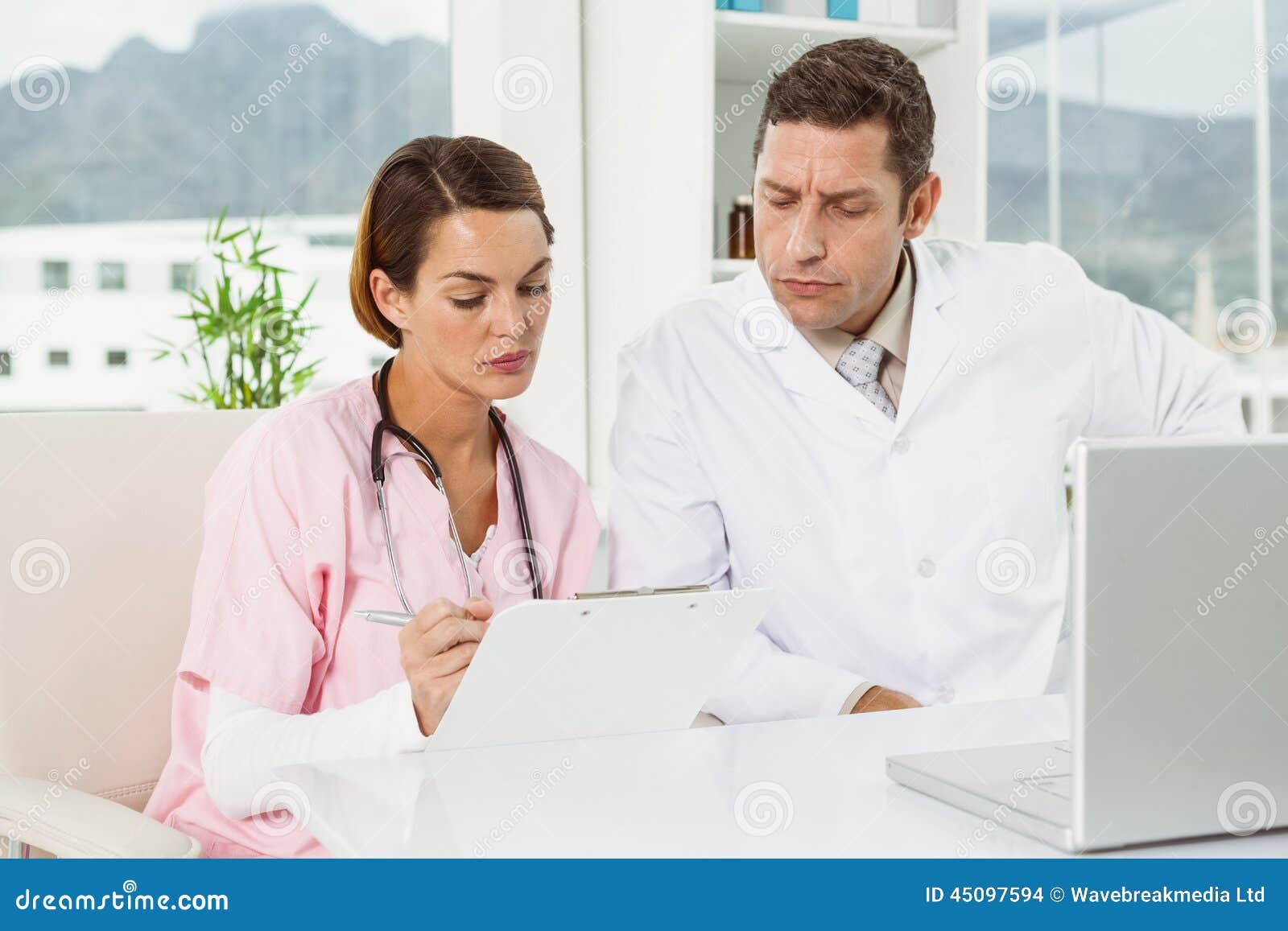 Doctors Reading Reports while Using Laptop at Medical Office Stock ...