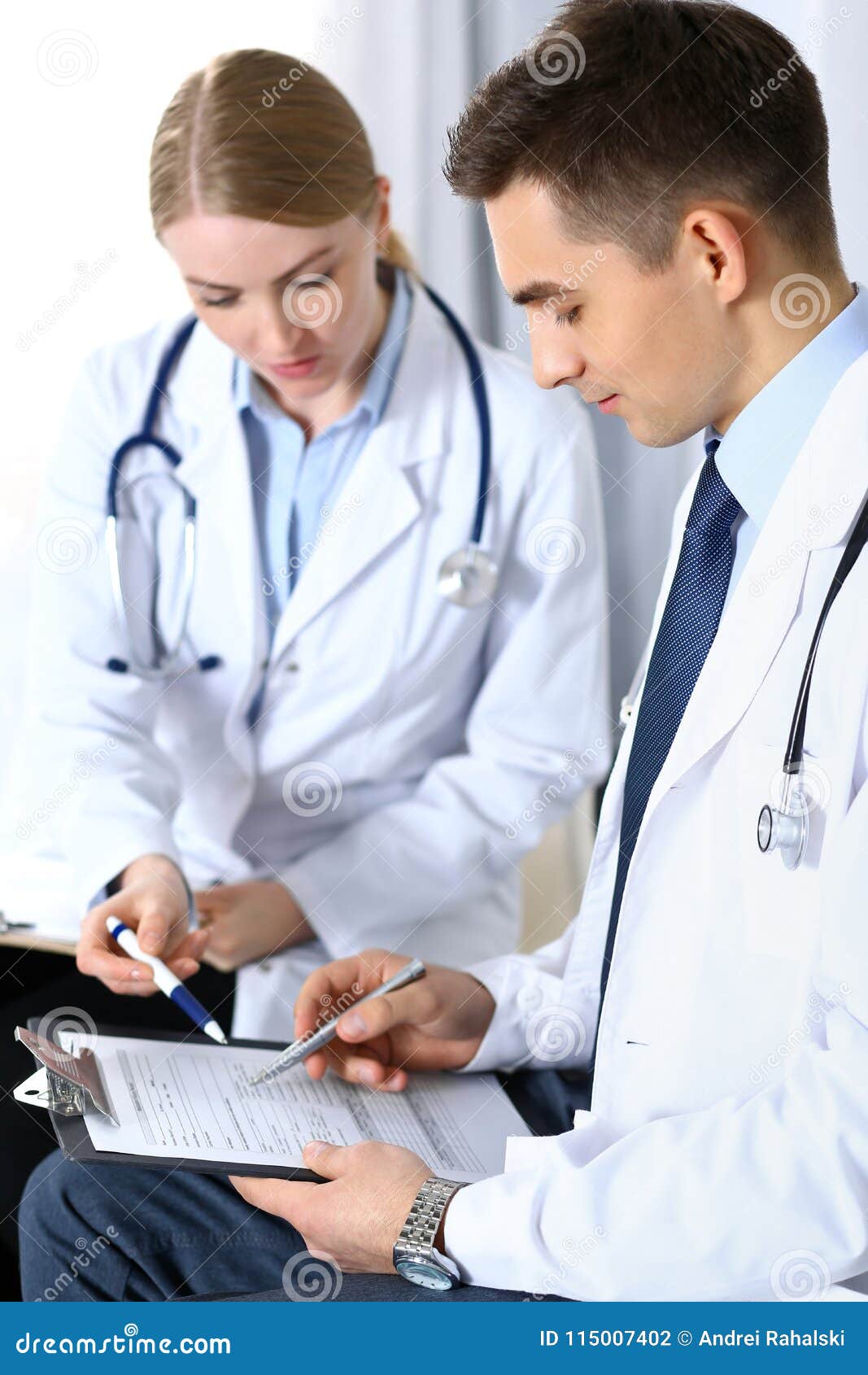 Doctors Writing Papers Using Clipboard. Physicians Discussing ...