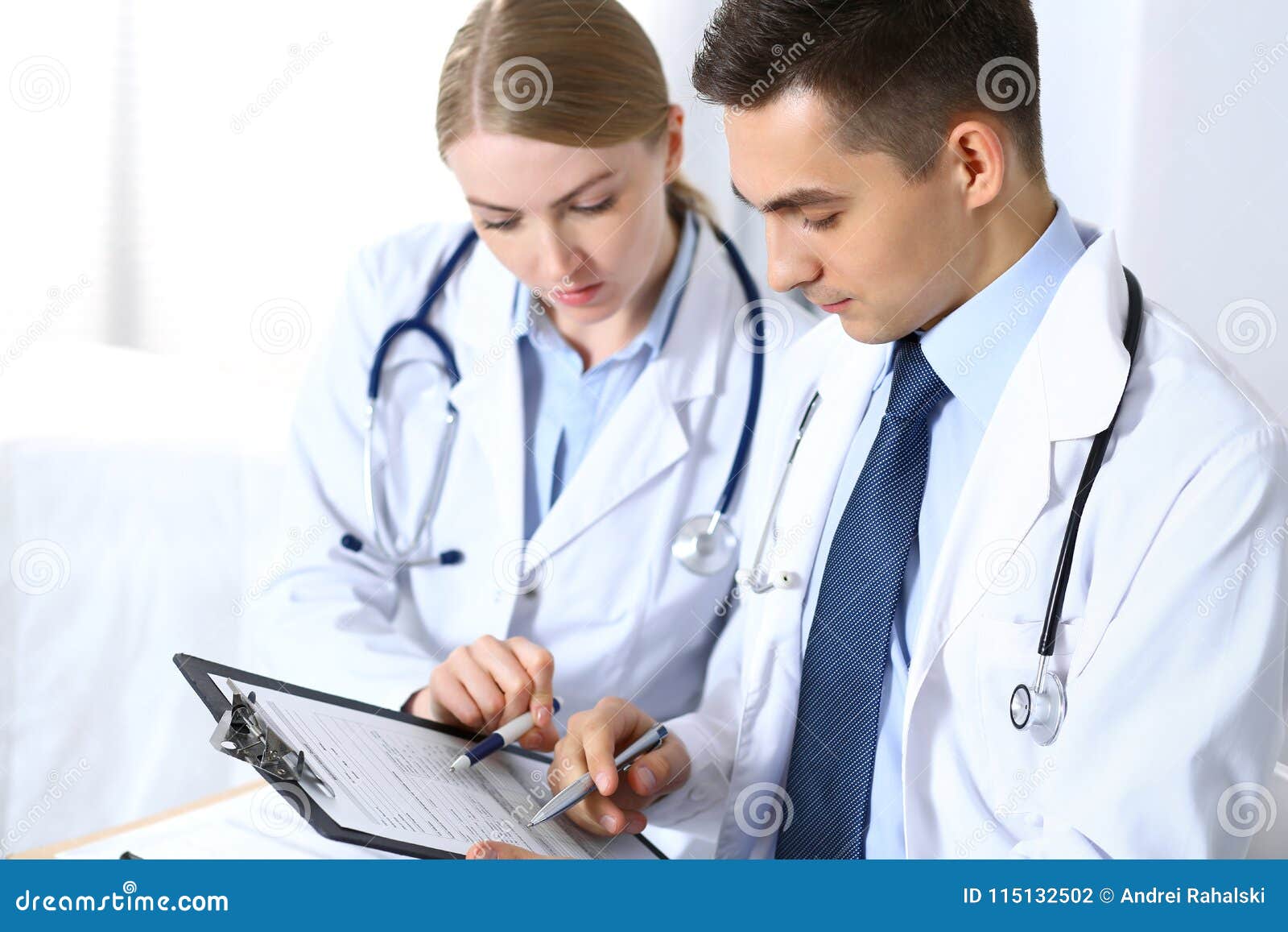 Doctors Writing Papers Using Clipboard. Physicians Discussing ...
