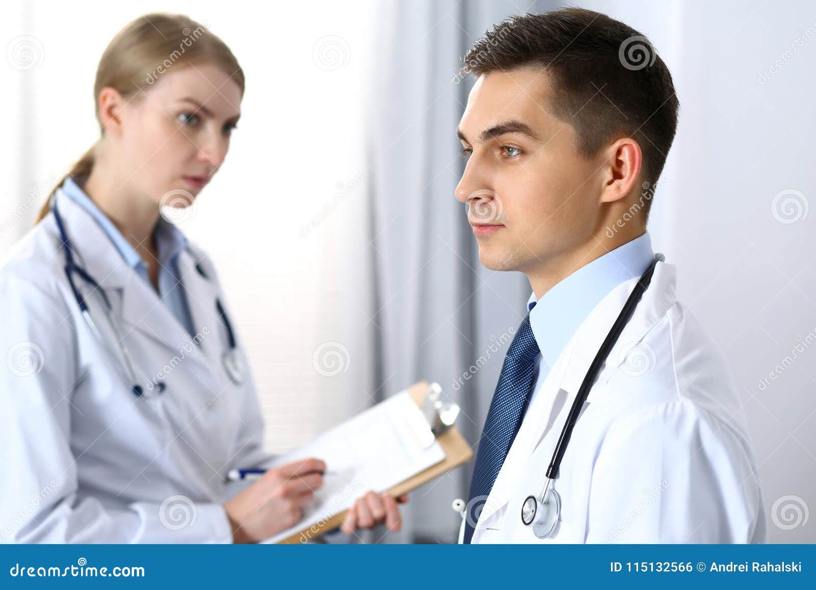 Doctors Writing Papers Using Clipboard. Physicians Discussing ...
