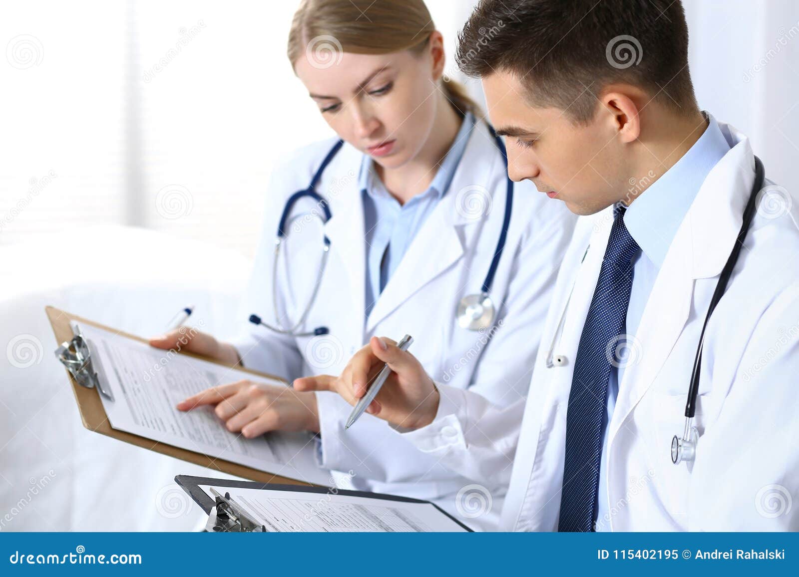 Doctors Writing Papers Using Clipboard. Physicians Discussing ...