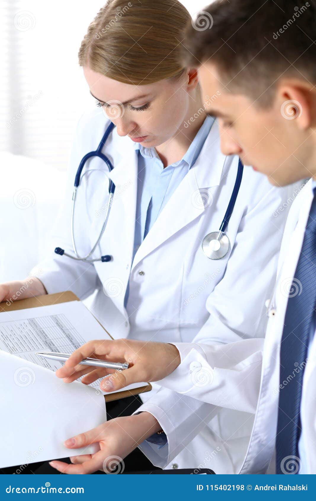 Doctors Writing Papers Using Clipboard. Physicians Discussing ...