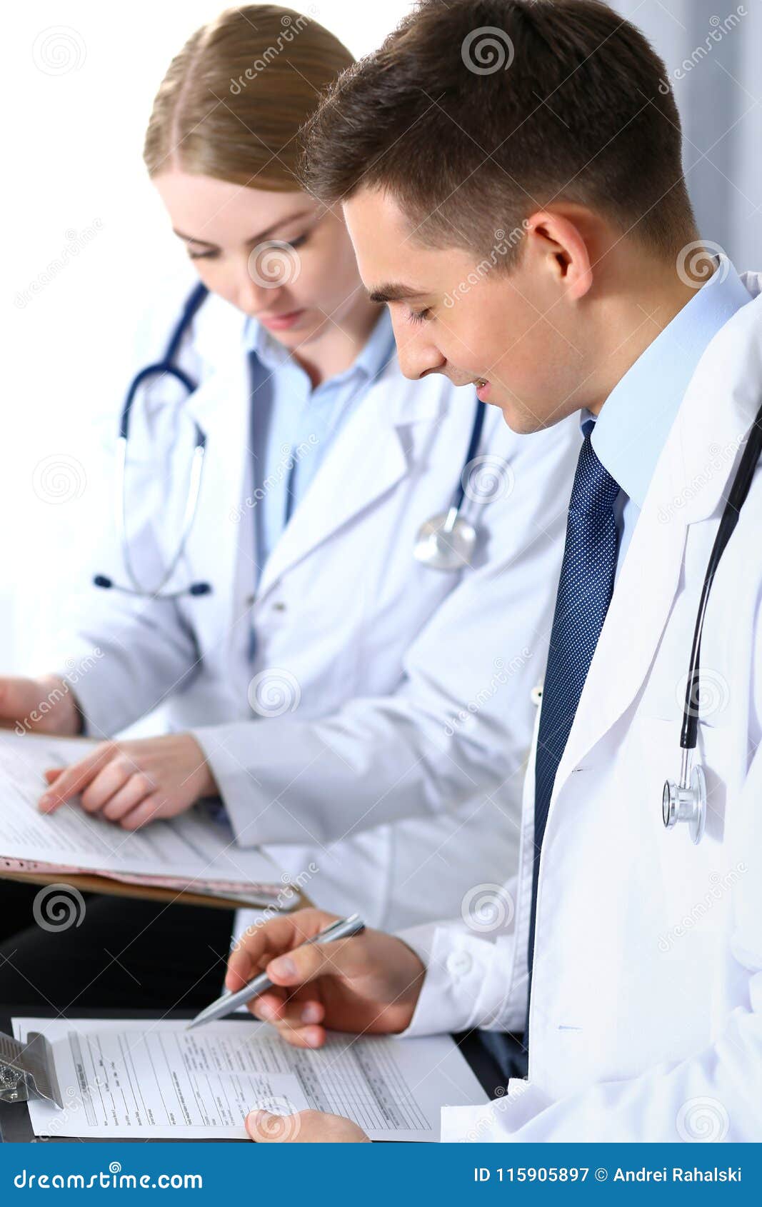 Doctors Writing Papers Using Clipboard. Physicians Discussing ...