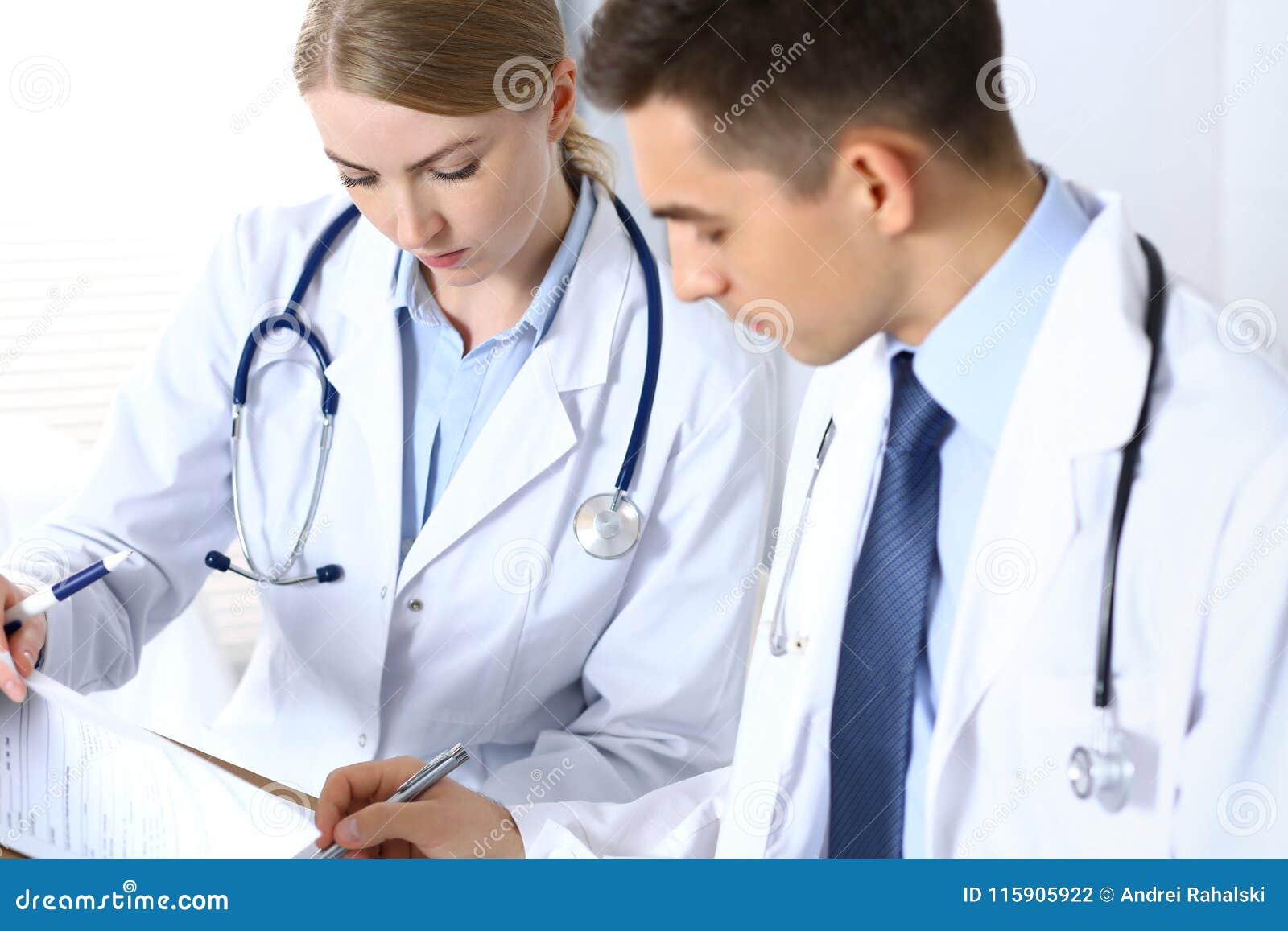 Doctors Writing Papers Using Clipboard. Physicians Discussing ...