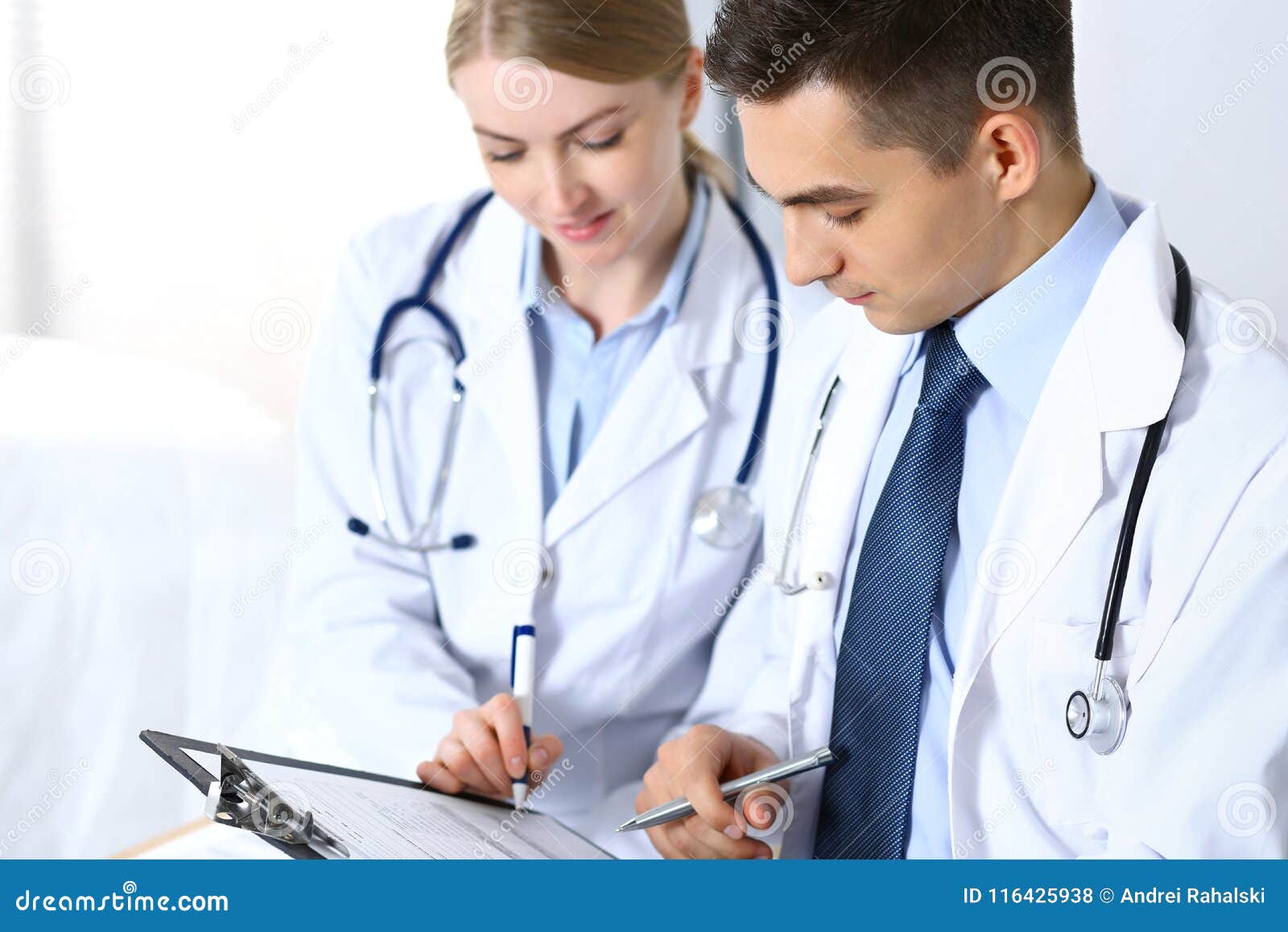 Doctors Writing Papers Using Clipboard. Physicians Discussing ...