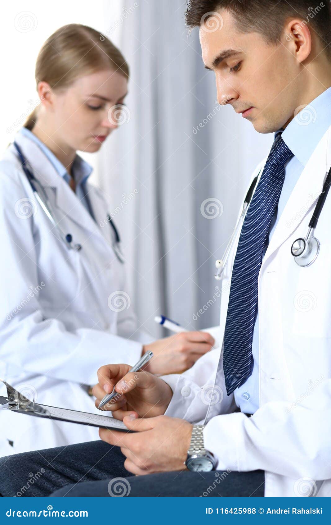 Doctors Writing Papers Using Clipboard. Physicians Discussing ...