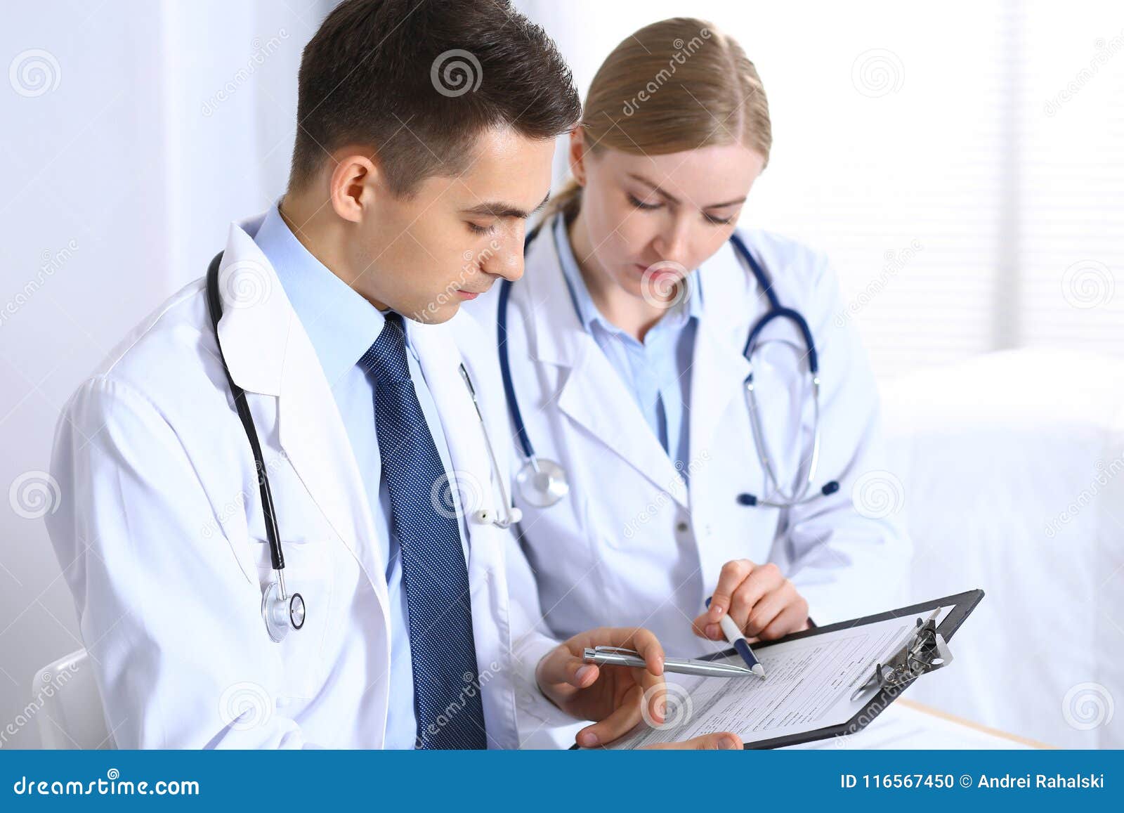 Doctors Writing Papers Using Clipboard. Physicians Discussing ...