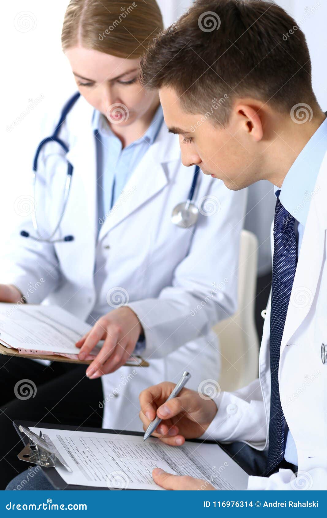 Doctors Writing Papers Using Clipboard. Physicians Discussing ...