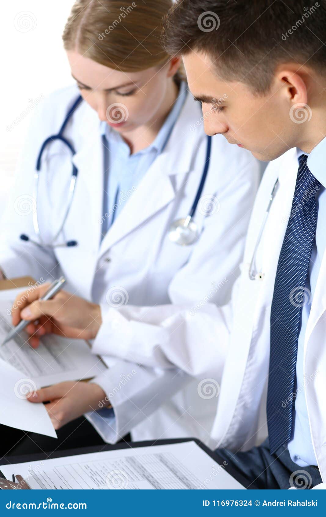 Doctors Writing Papers Using Clipboard. Physicians Discussing ...