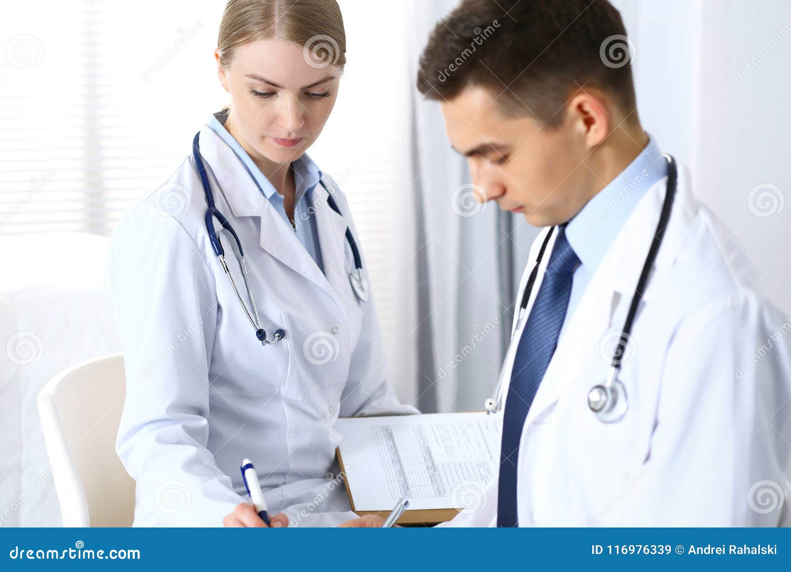 Doctors Writing Papers Using Clipboard. Physicians Discussing ...