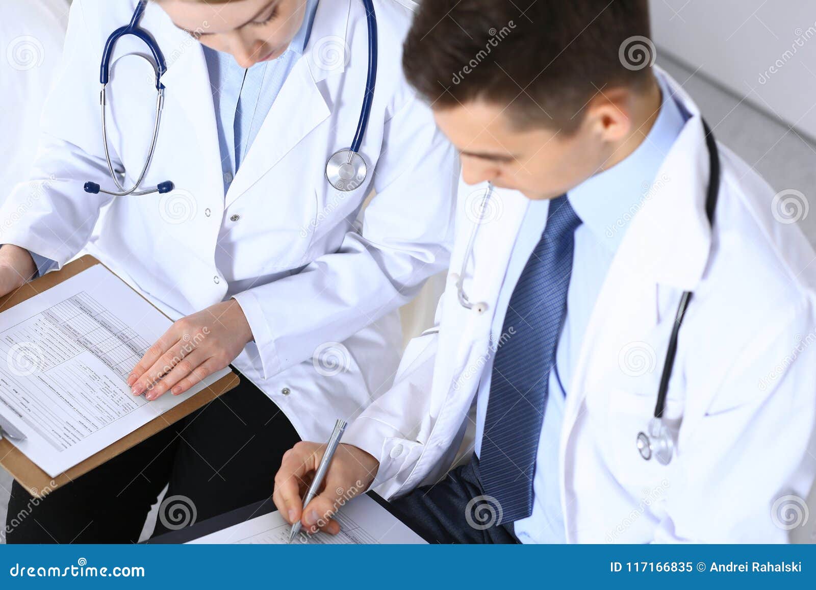 Doctors Writing Papers Using Clipboard. Physicians Discussing ...
