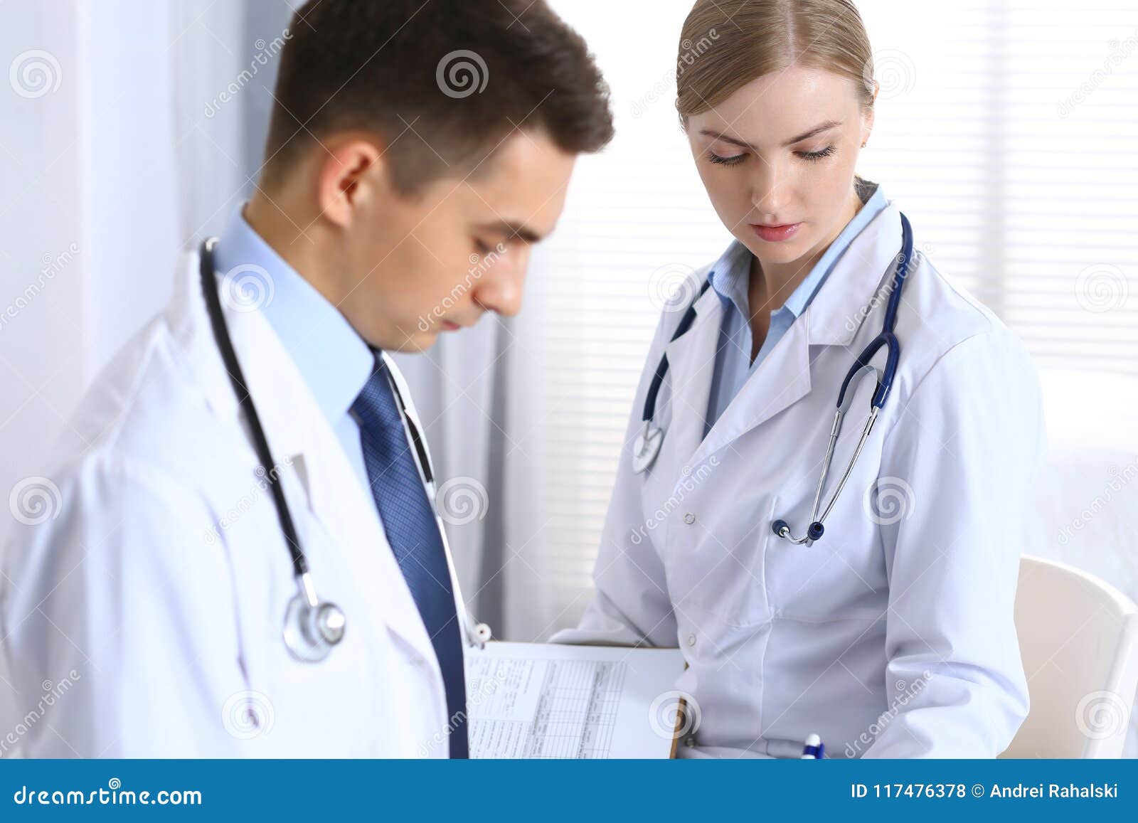 Doctors Writing Papers Using Clipboard. Physicians Discussing ...