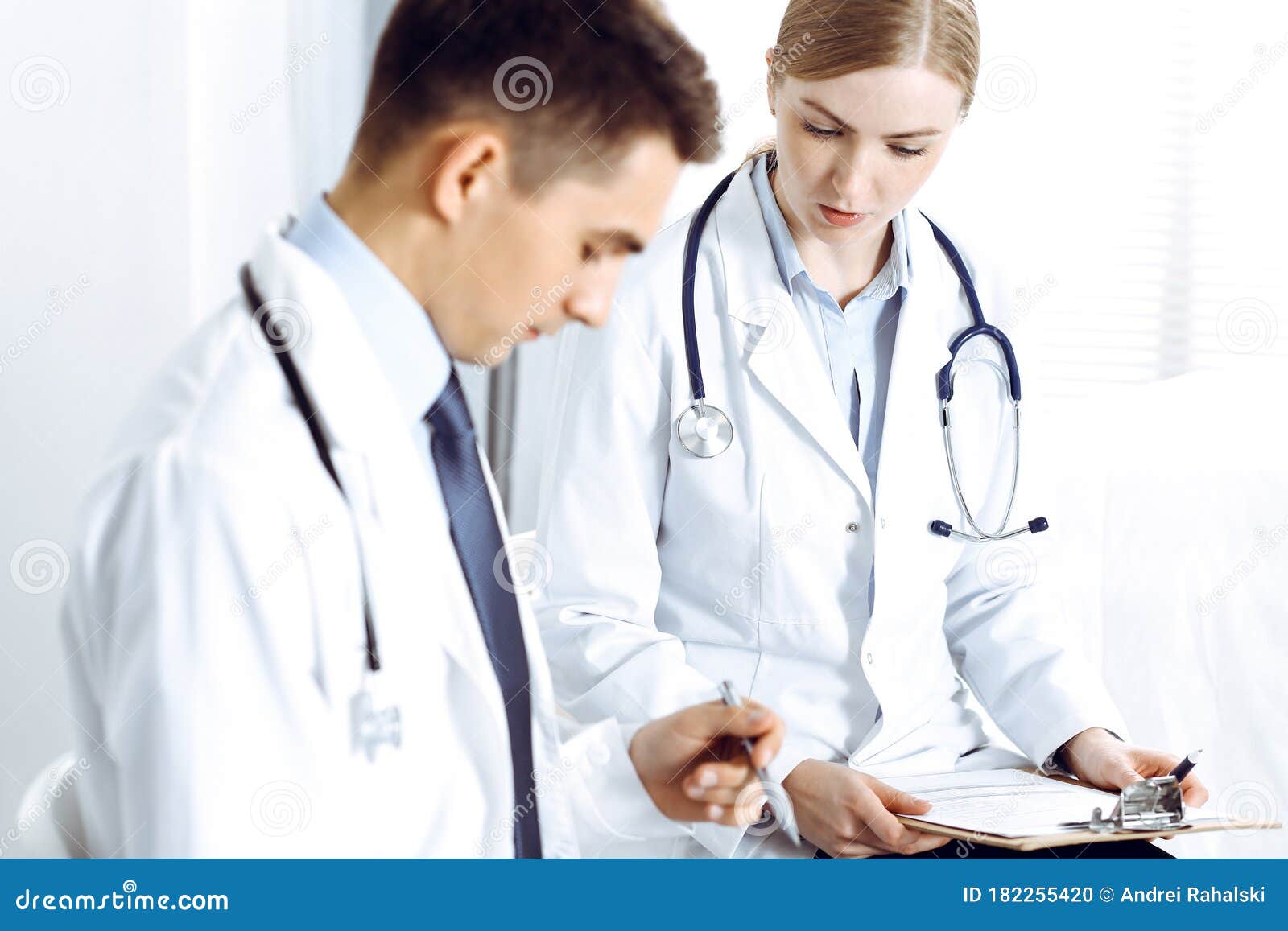 Doctors Writing Papers Using Clipboard. Physicians Discussing ...