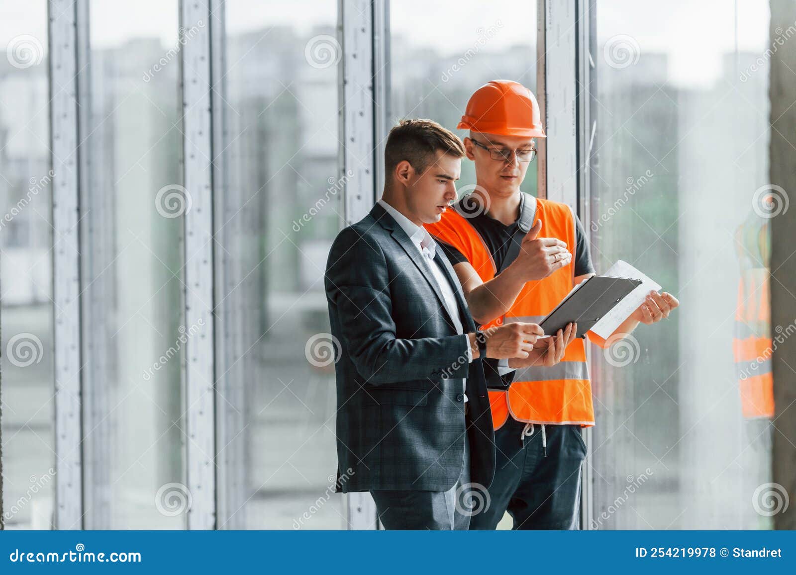 With Documents. Man in Suit and Handyman in Orange Protective Wear is ...