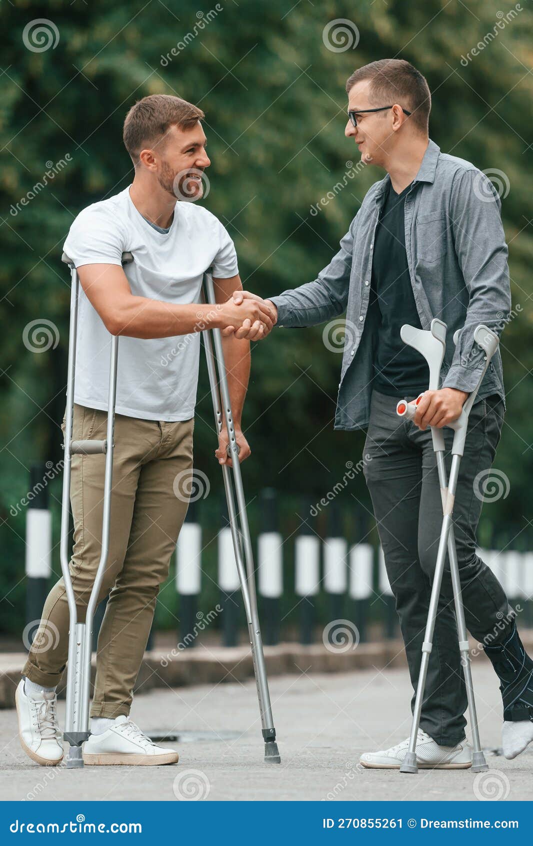 Doing Handshake. Two Men with Crutches is Outdoors on the Road Stock ...