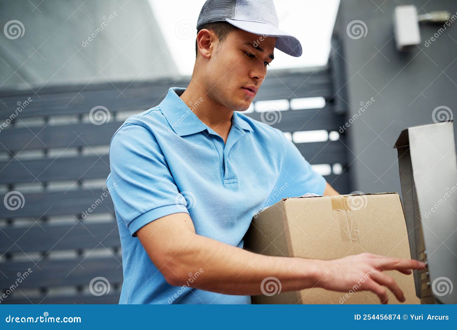 Doing His Delivery Rounds. a Courier Ringing an Intercom while Making a ...