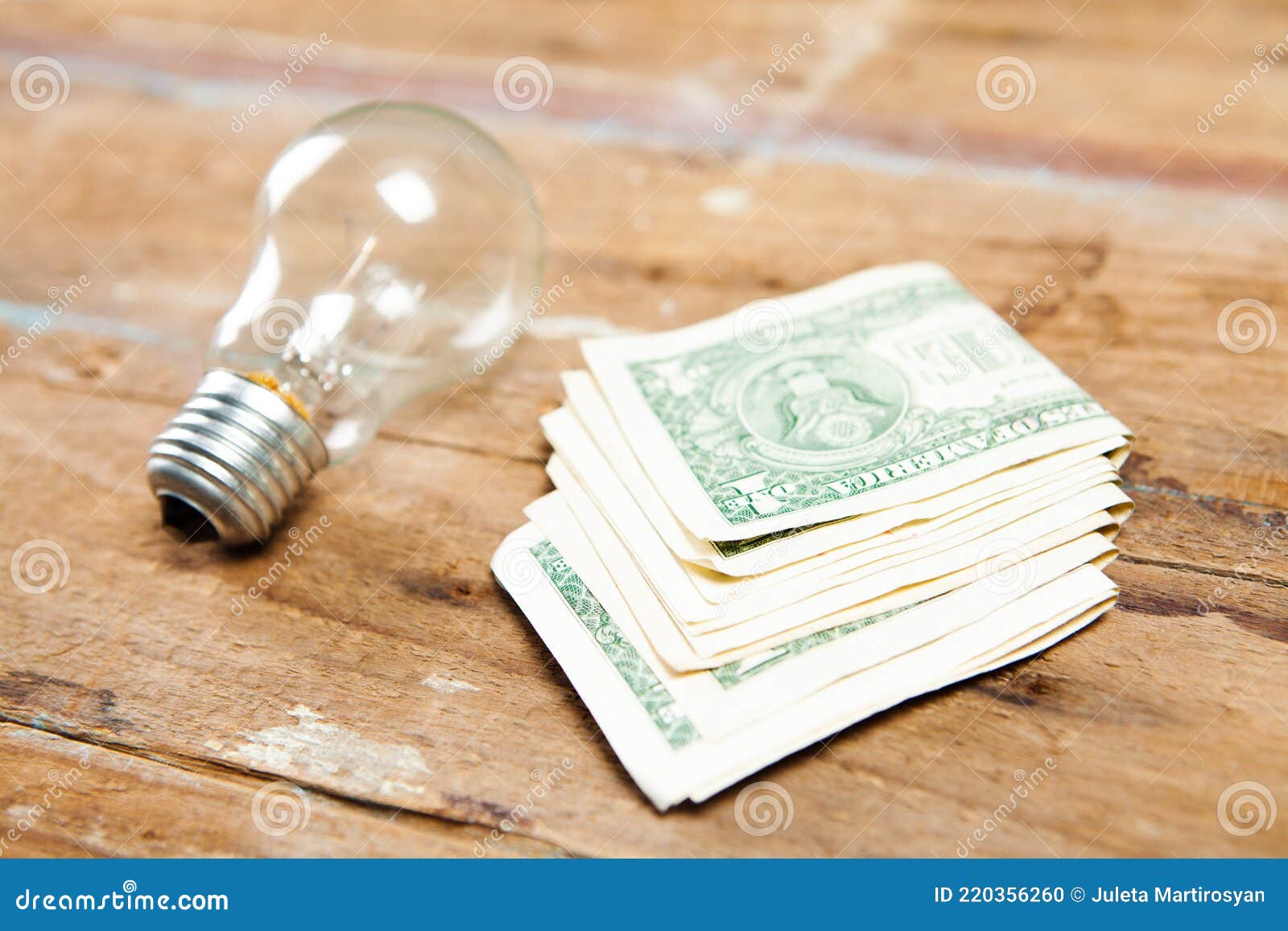Dollar Bills and Light Bulb on Wooden Table Stock Photo - Image of ...