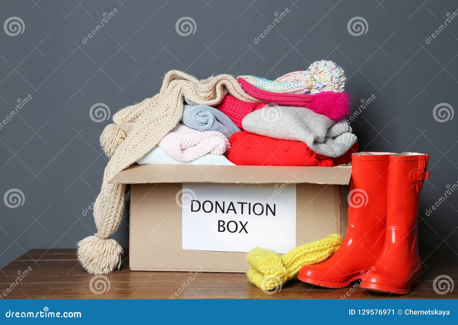 Donation Box with Knitted Clothes and Rubber Boots on Table Stock Image ...