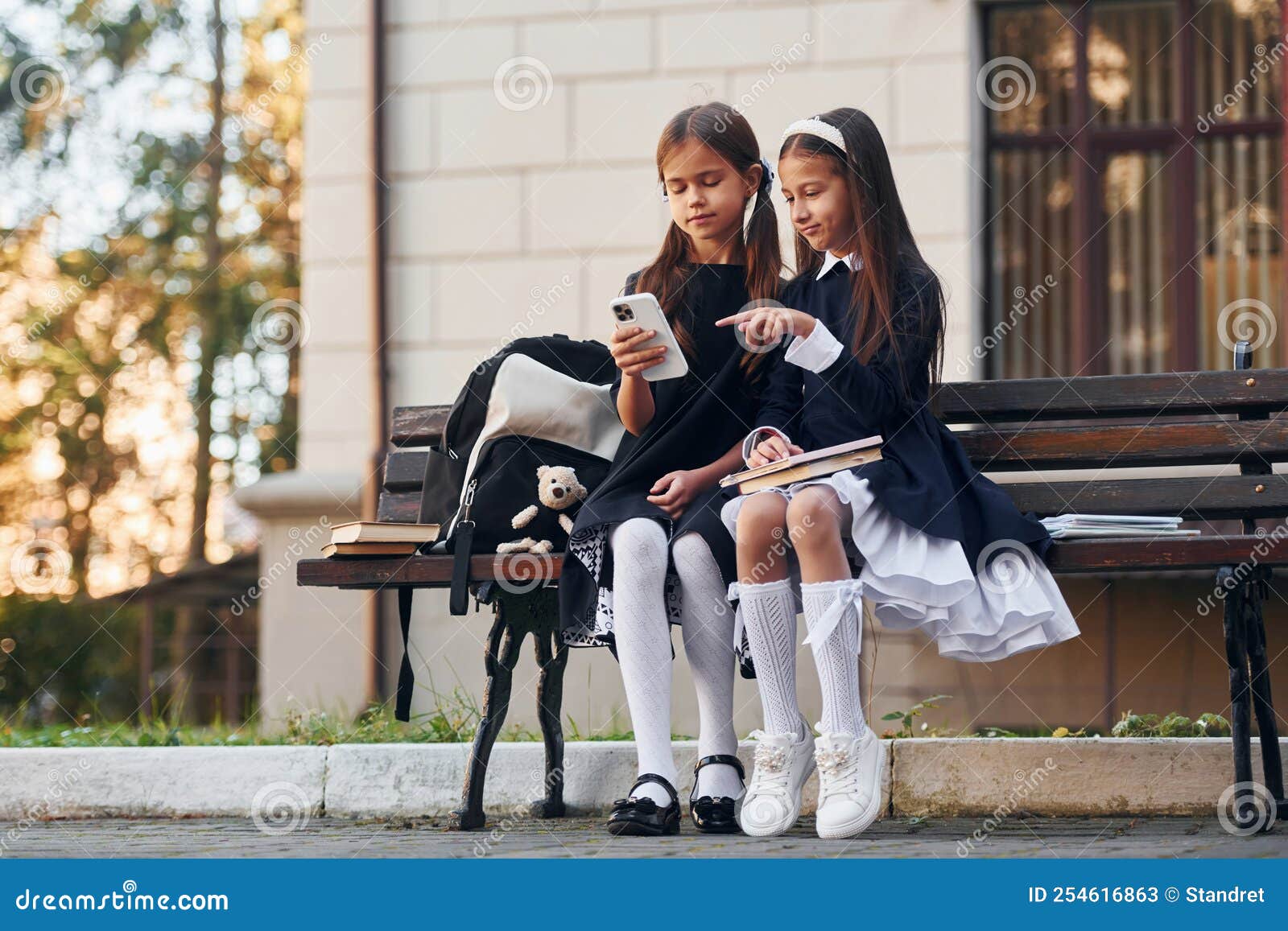 Dos Colegialas Sentadas Afuera Juntas Cerca Del Edificio Escolar Imagen ...