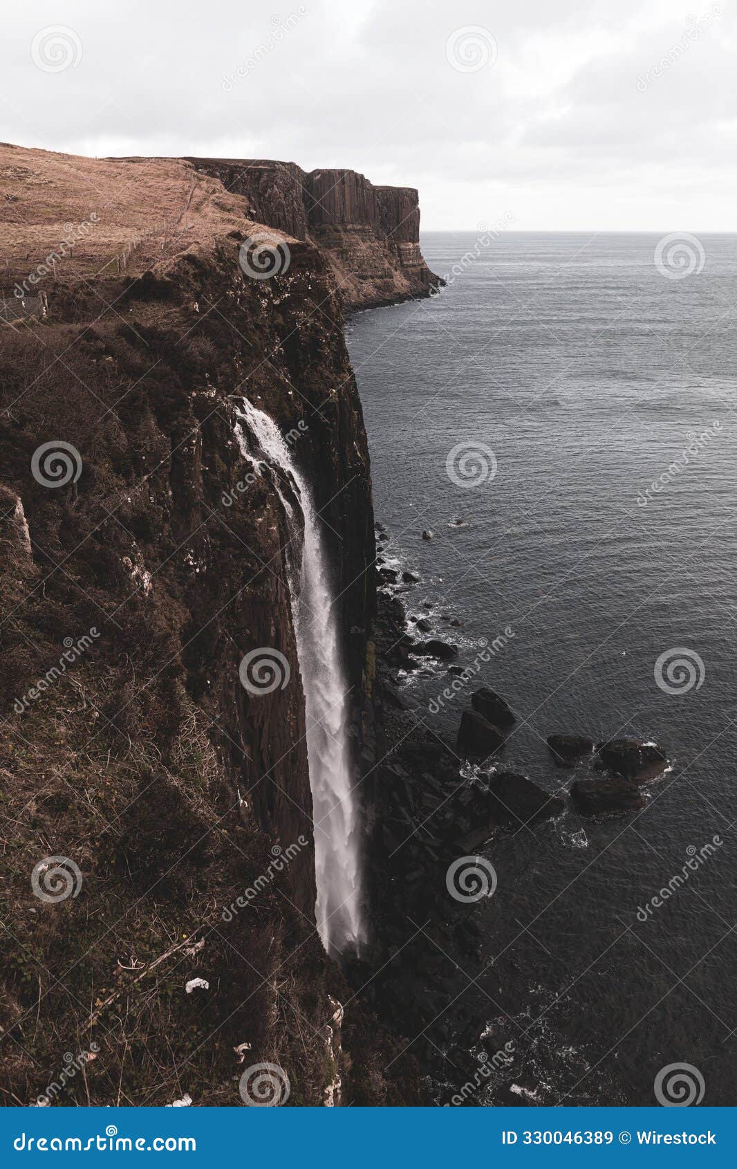 Dramatic Coastal Cliff with a Waterfall Cascading into the Ocean Under ...