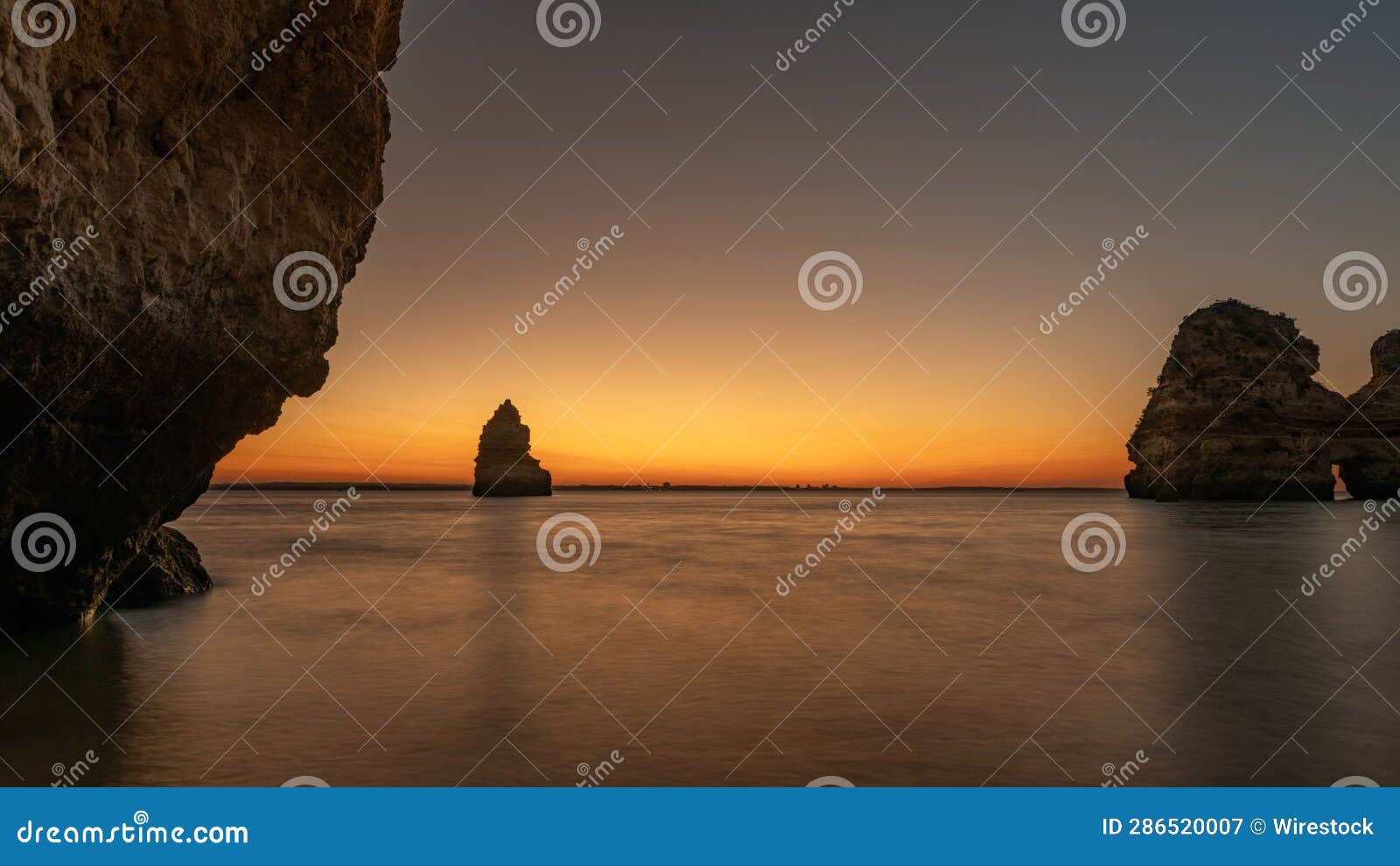 Sunset and Rocks on the Beach at Dusk with the Sun Setting Stock Image ...