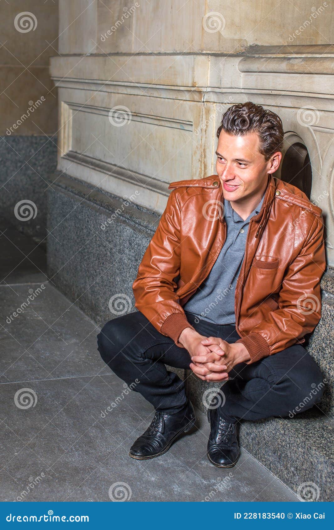 A Young Handsome Guy is Squatting in the Corner of a Building, Relaxing ...