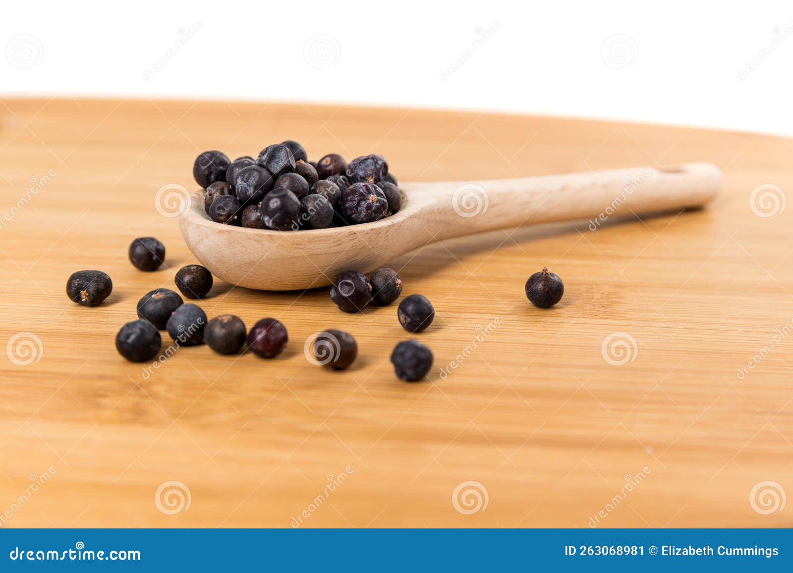 Dried Juniper Berries Scattered Around a Wood Spoon Over Wood Board ...