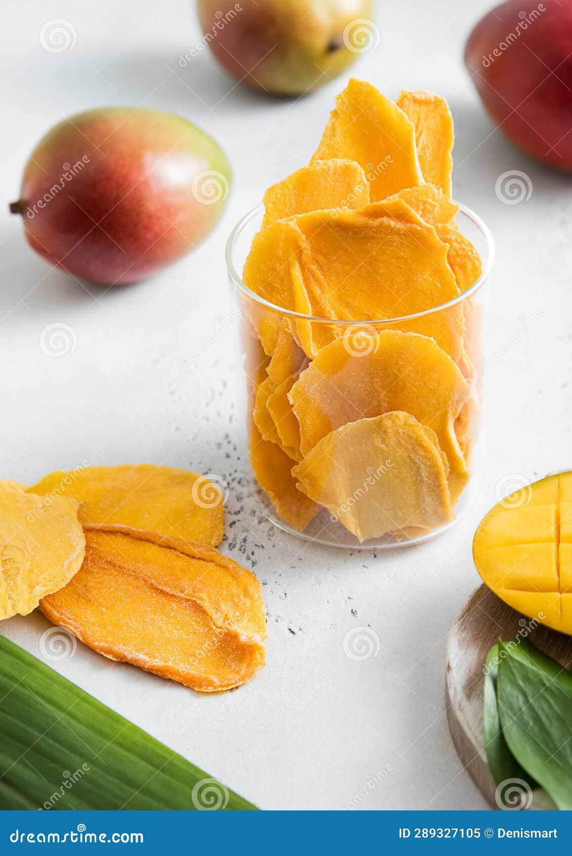 Dried Mango Pieces in Glass Jar and Raw Fruit on Light Background Stock ...