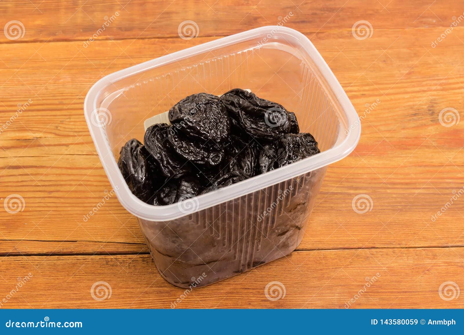 Dried Prunes in Plastic Container on a Rustic Table Stock Image - Image ...
