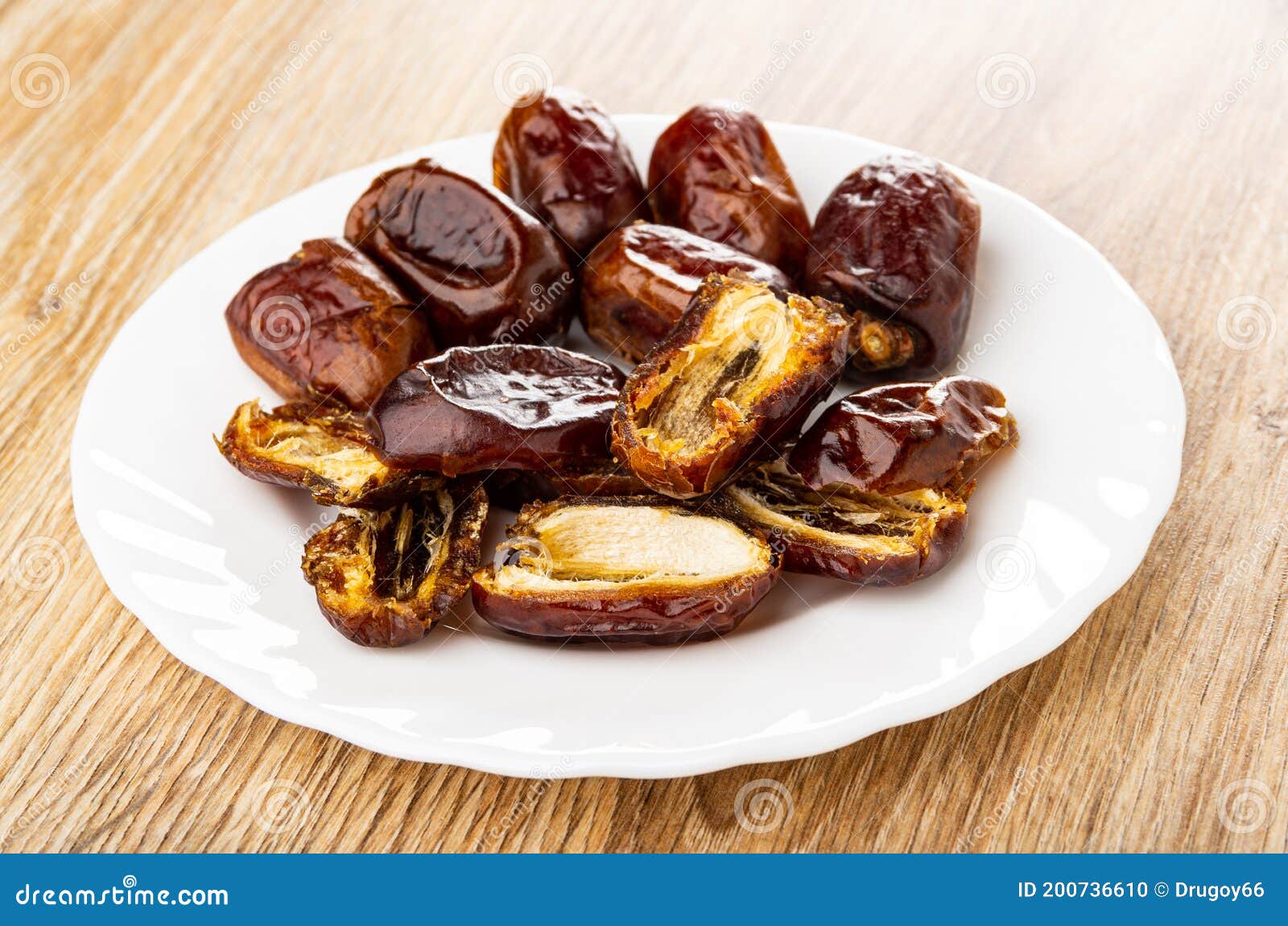 Dried Whole Dates, Halves of Dates in Plate on Wooden Table Stock Photo ...